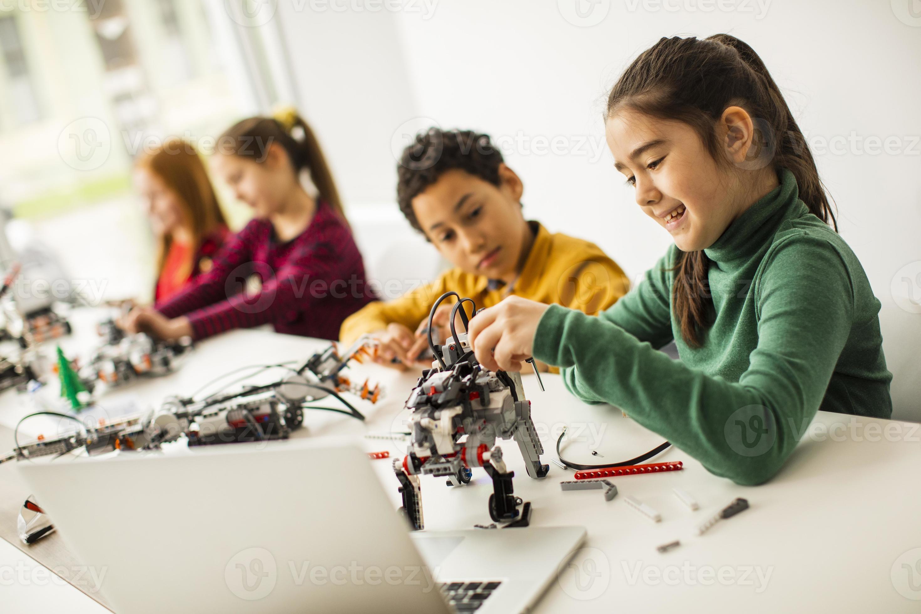 Happy kids programming electric toys and robots at robotics classroom ...