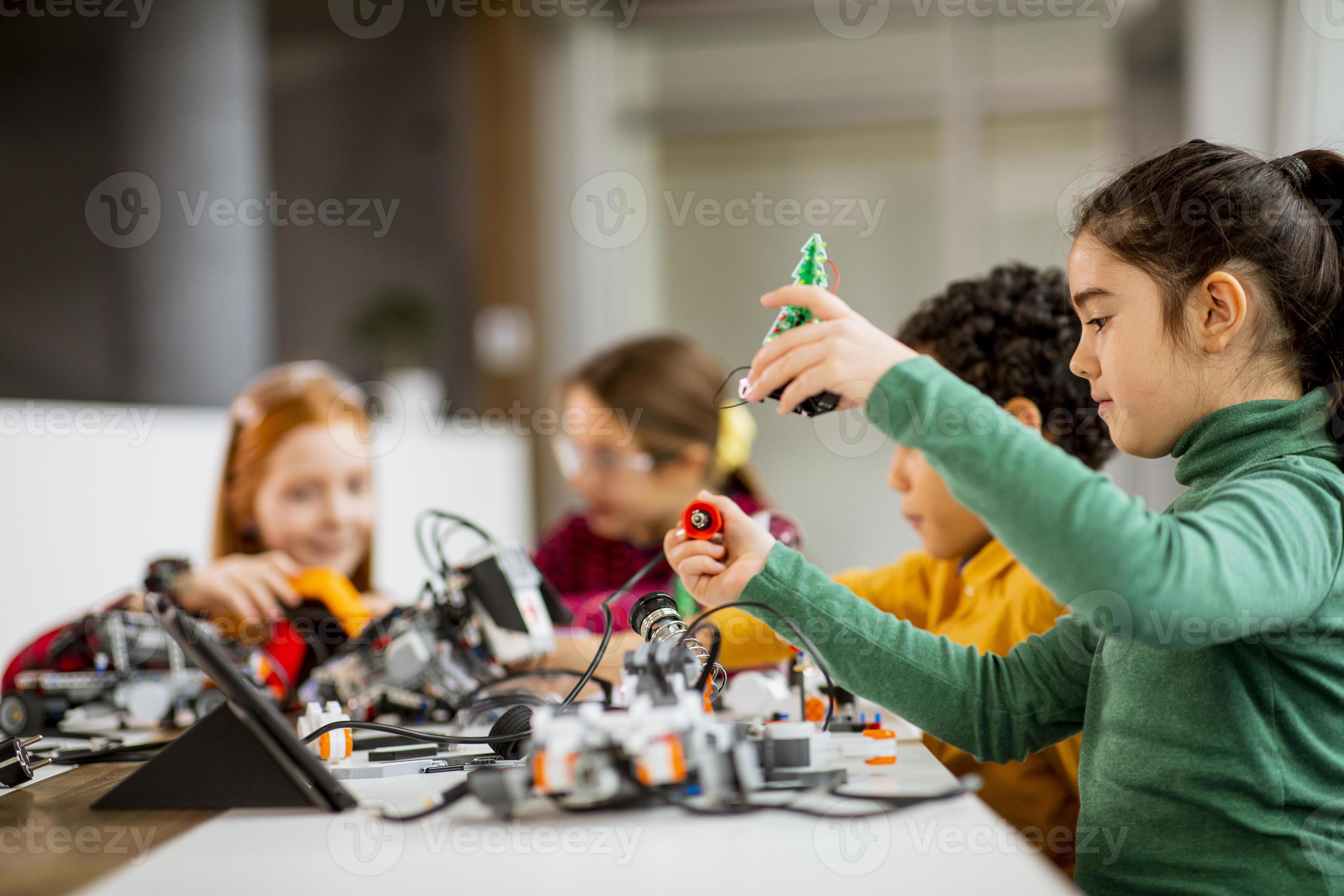 Happy kids programming electric toys and robots at robotics classroom ...
