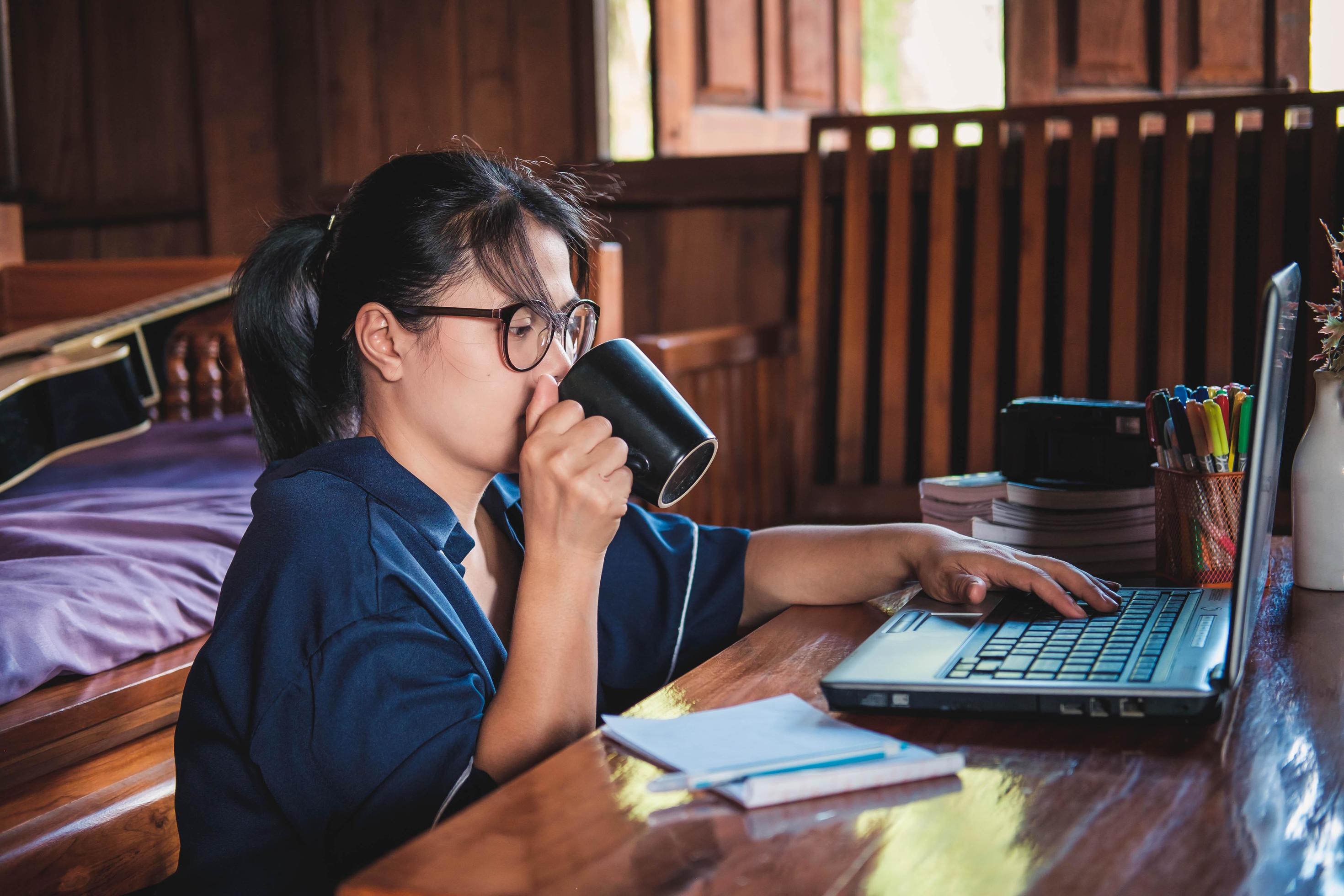 Woman having a coffee sitting on a floor in home writing down notes ...