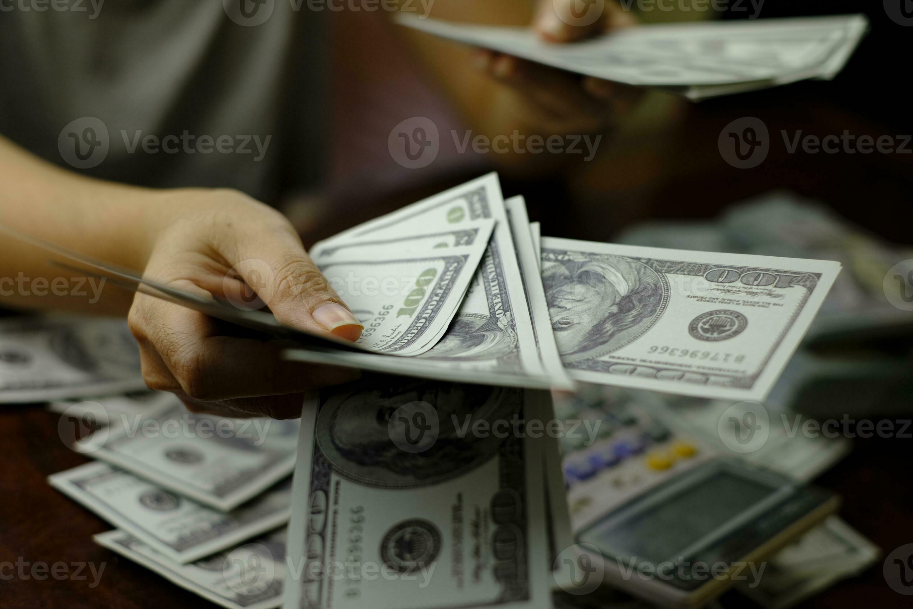 Businessmen women counting money on a stack of 100 US dollars banknotes ...