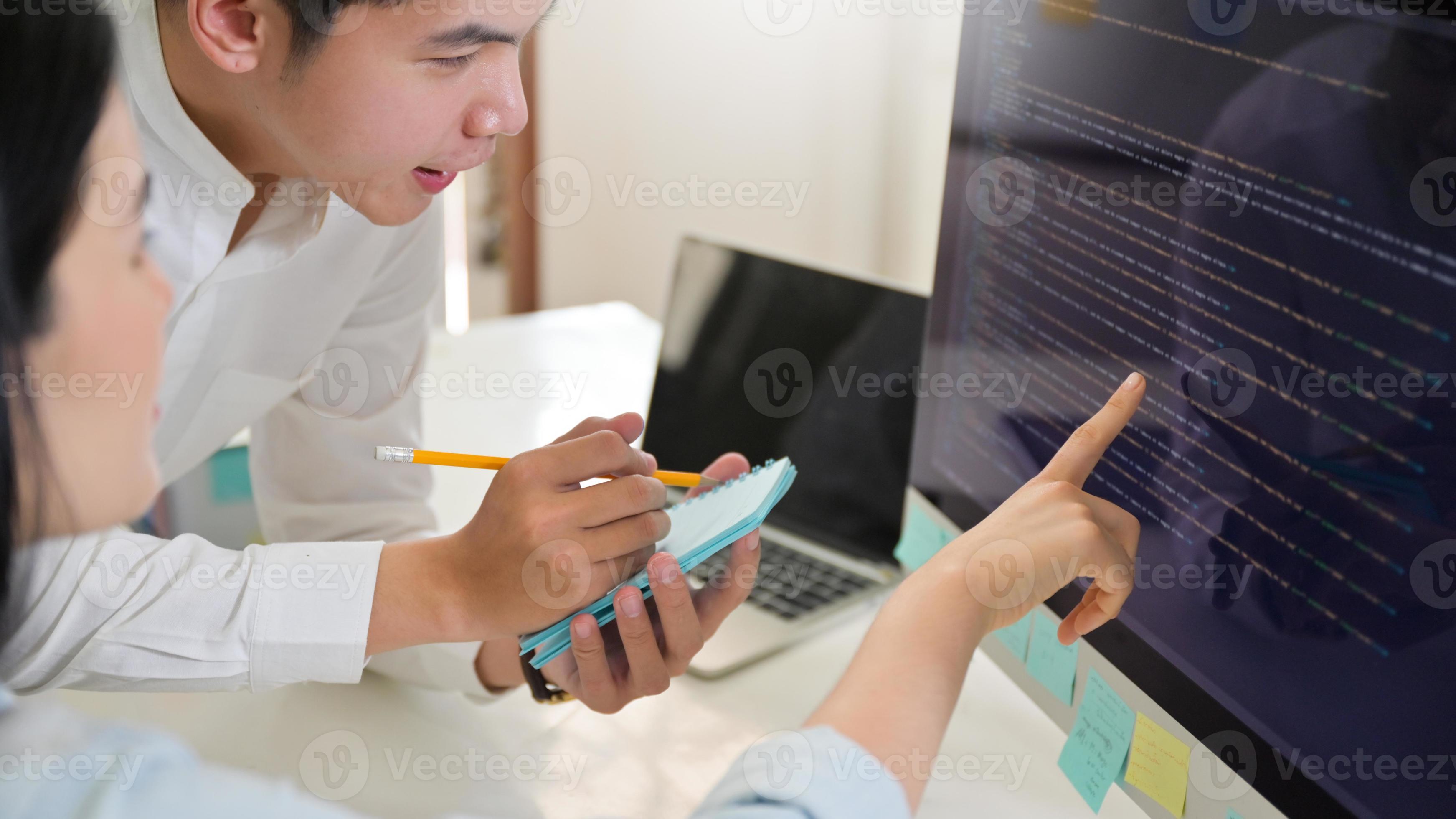 Male program analyst examining programs with female programmer on ...