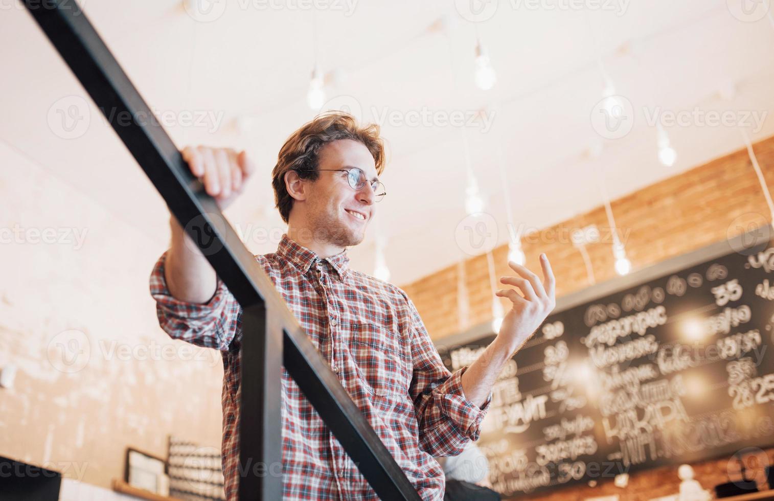 Thoughtful young man is sitting in confectionery shop. She is drinking ...