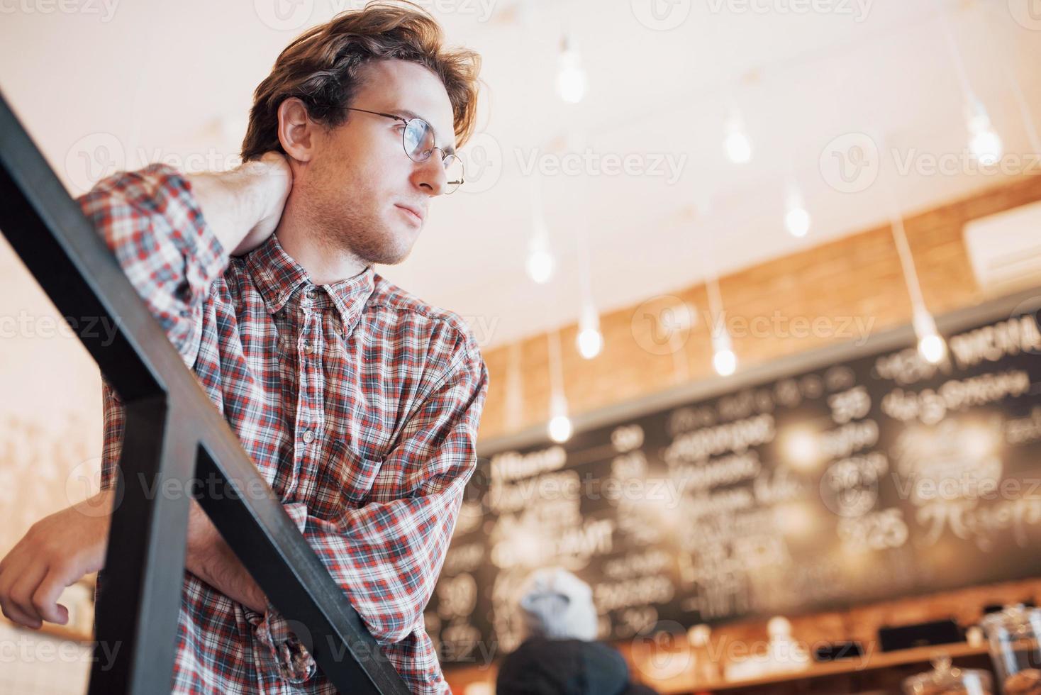 Thoughtful young man is sitting in confectionery shop. She is drinking ...