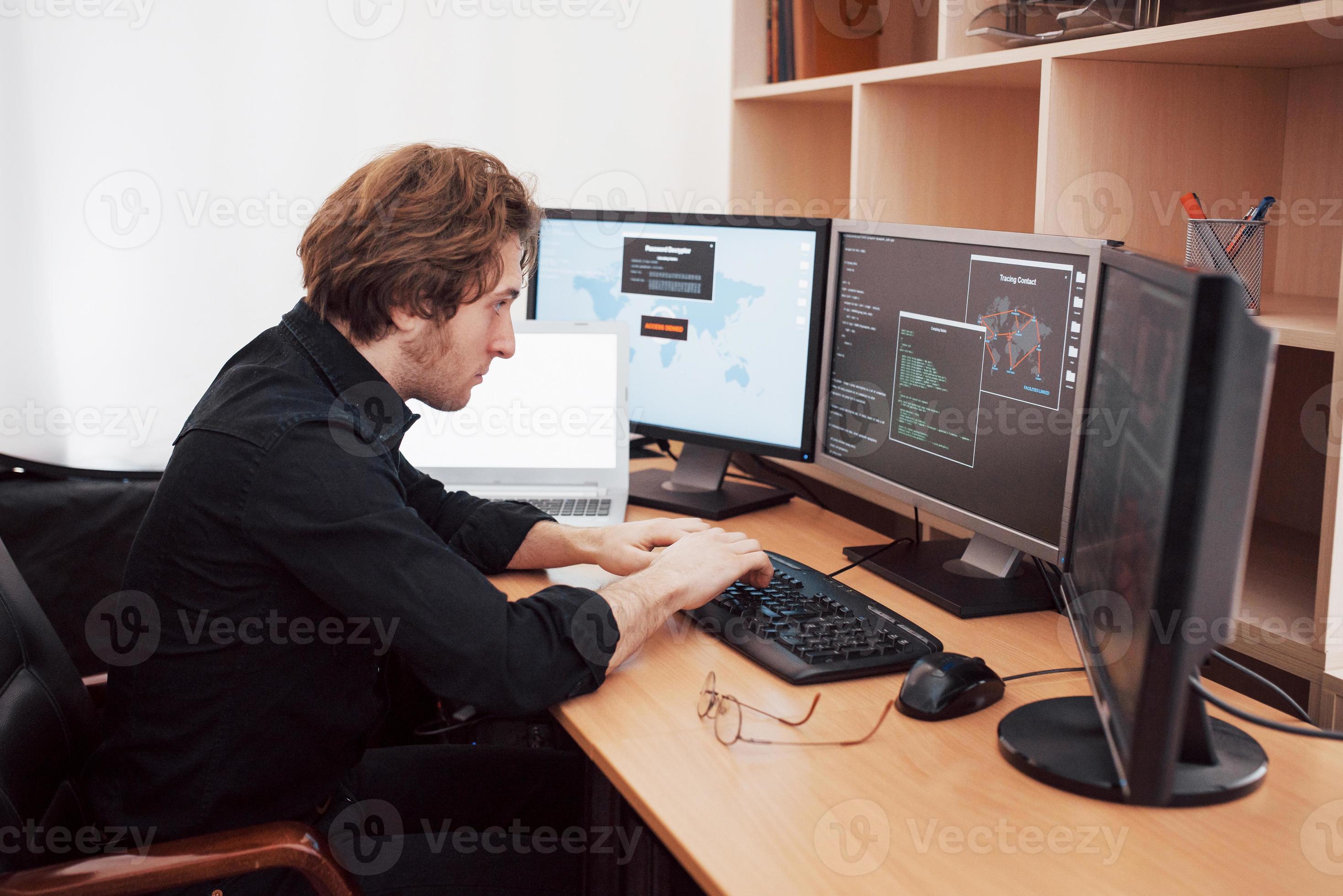 Male programmer working on desktop computer with many monitors at ...