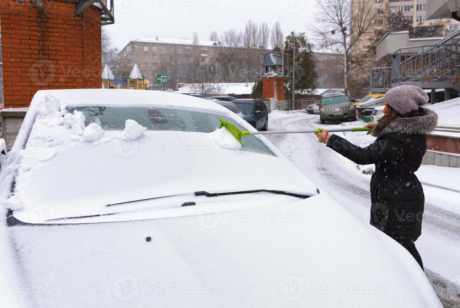 A young woman cleans snow from the surface of her car. 4703493 Stock ...