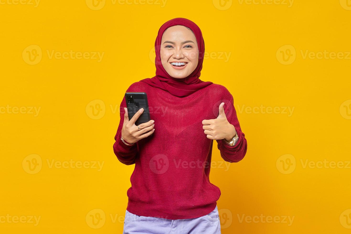 Portrait Of Cheerful Young Asian Woman Holding Mobile Phone And Showing
