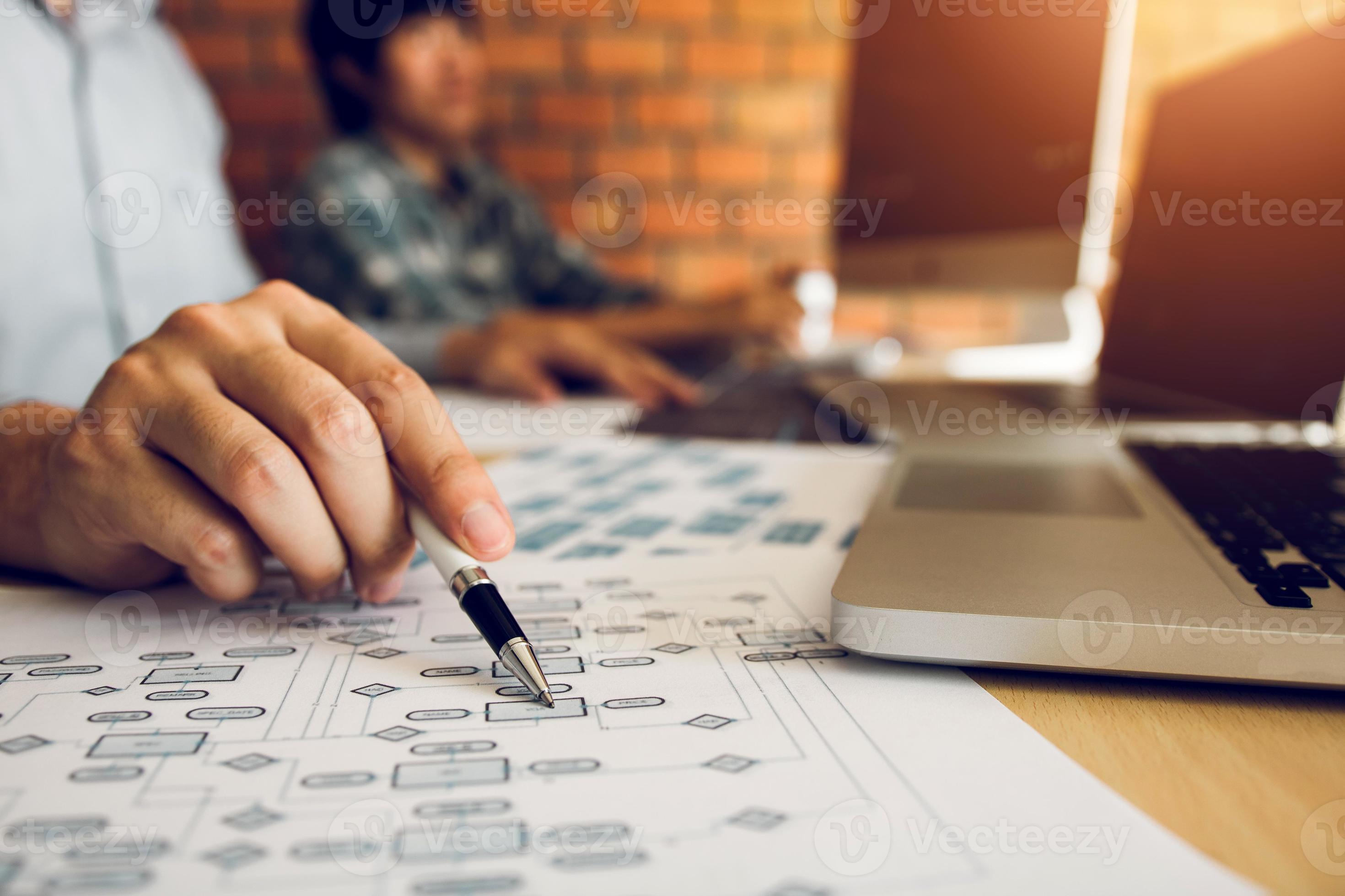 Software Developer Is Pointing To The Paper Working And Analyzing Together The Code Written Into