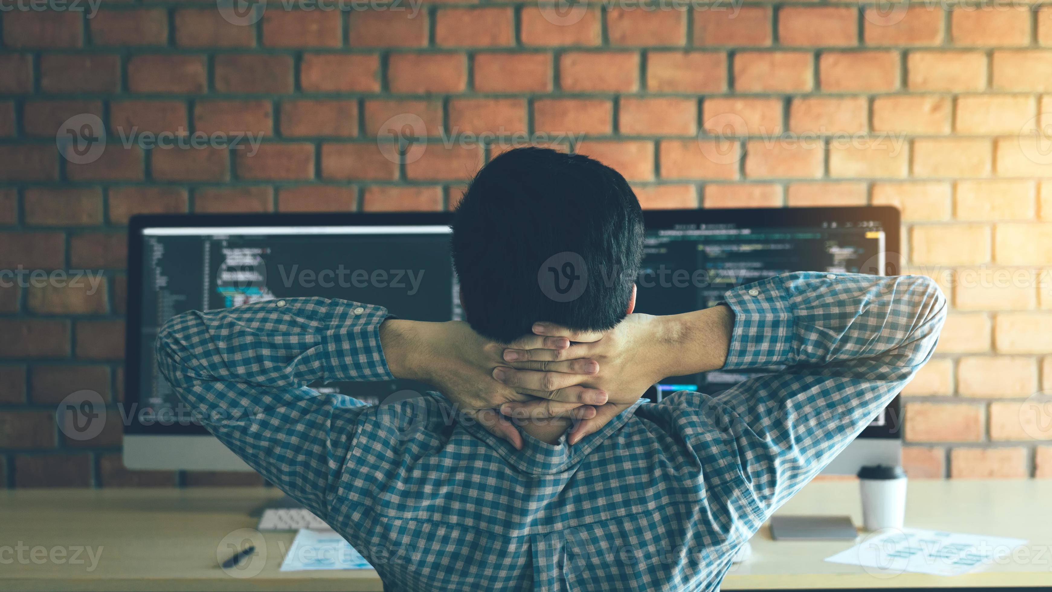 Asian programmers man are relaxing and looking at the code on the ...