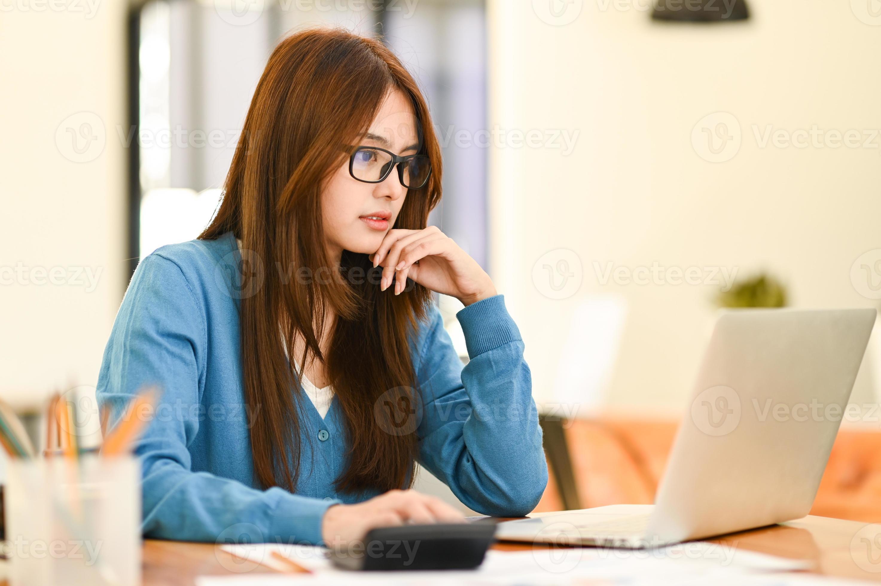 Young businesswoman wearing glasses working in the office with a laptop ...