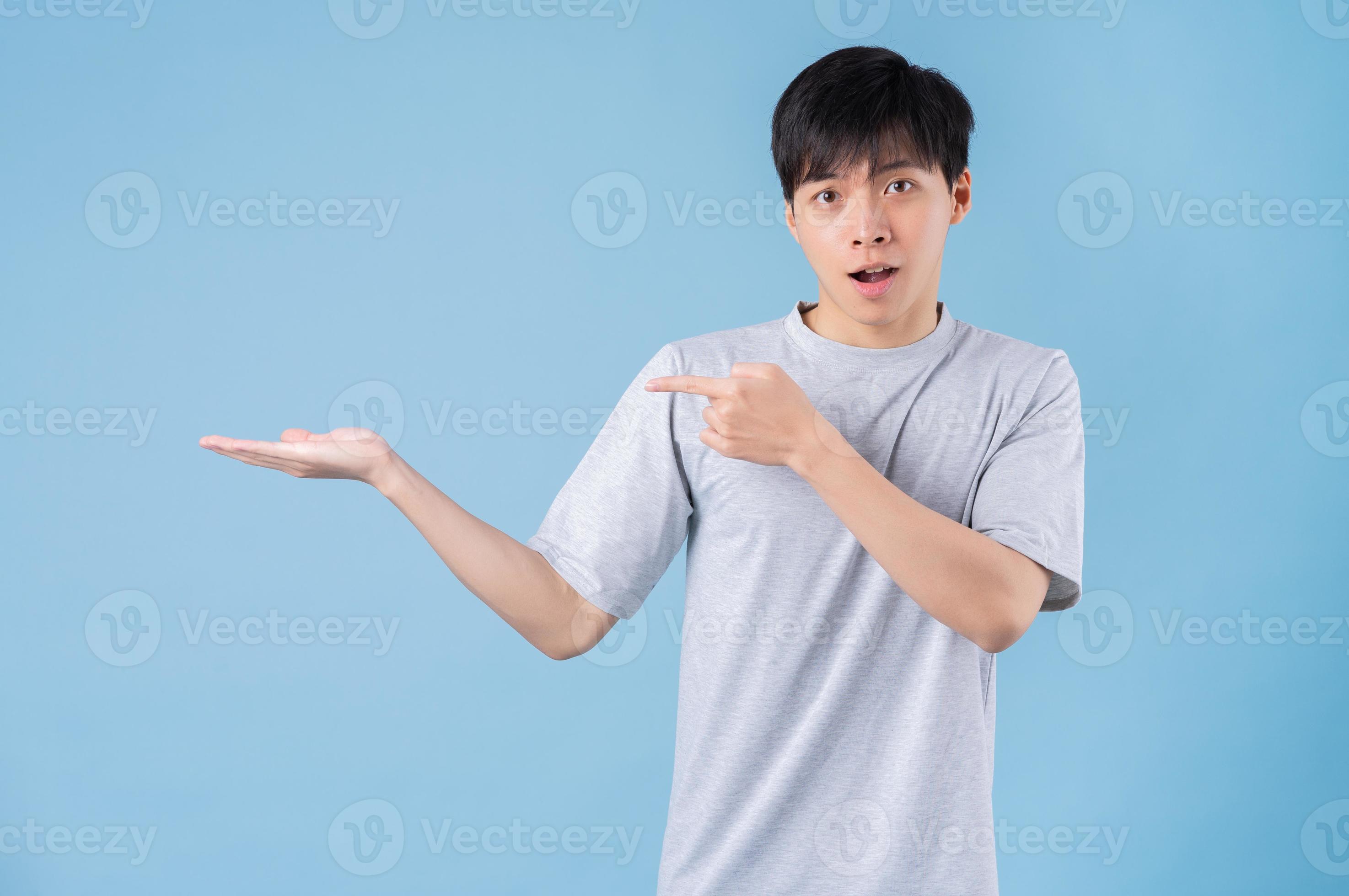 Young Asian man posing on blue background 5923018 Stock Photo at Vecteezy
