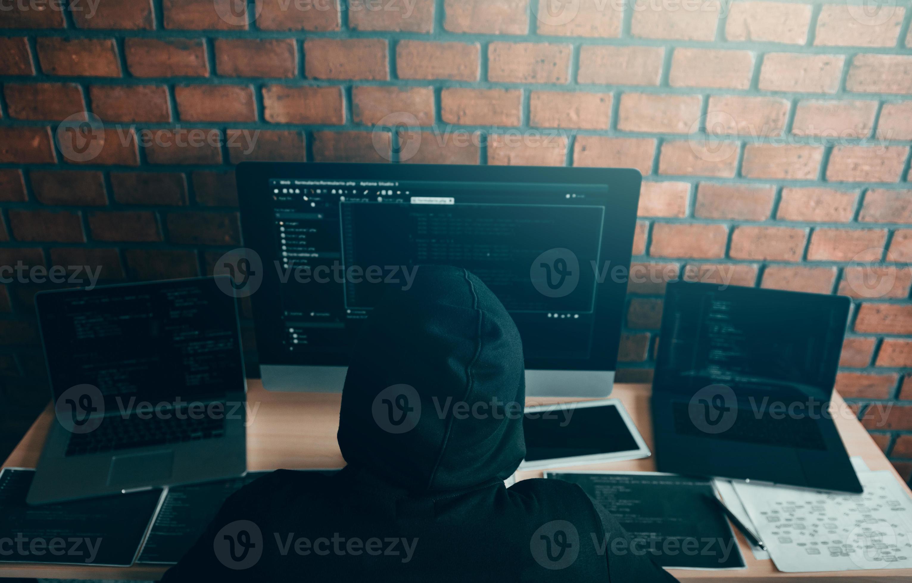 Hacker in the hood working with computer with hacking breaking into ...