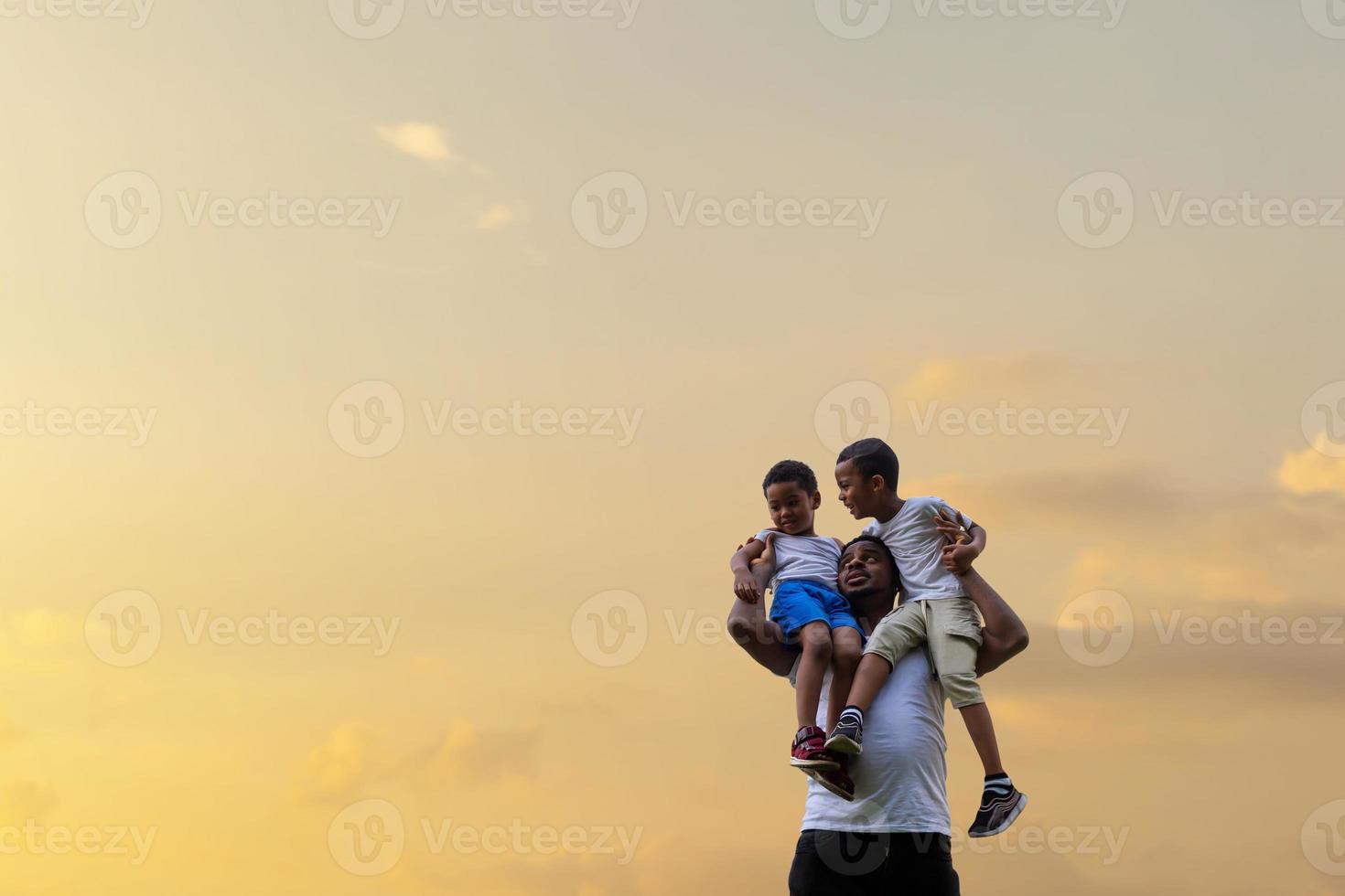 Happy father carrying two sons on shoulders, Cheerful African American kids on the shoulders of ...