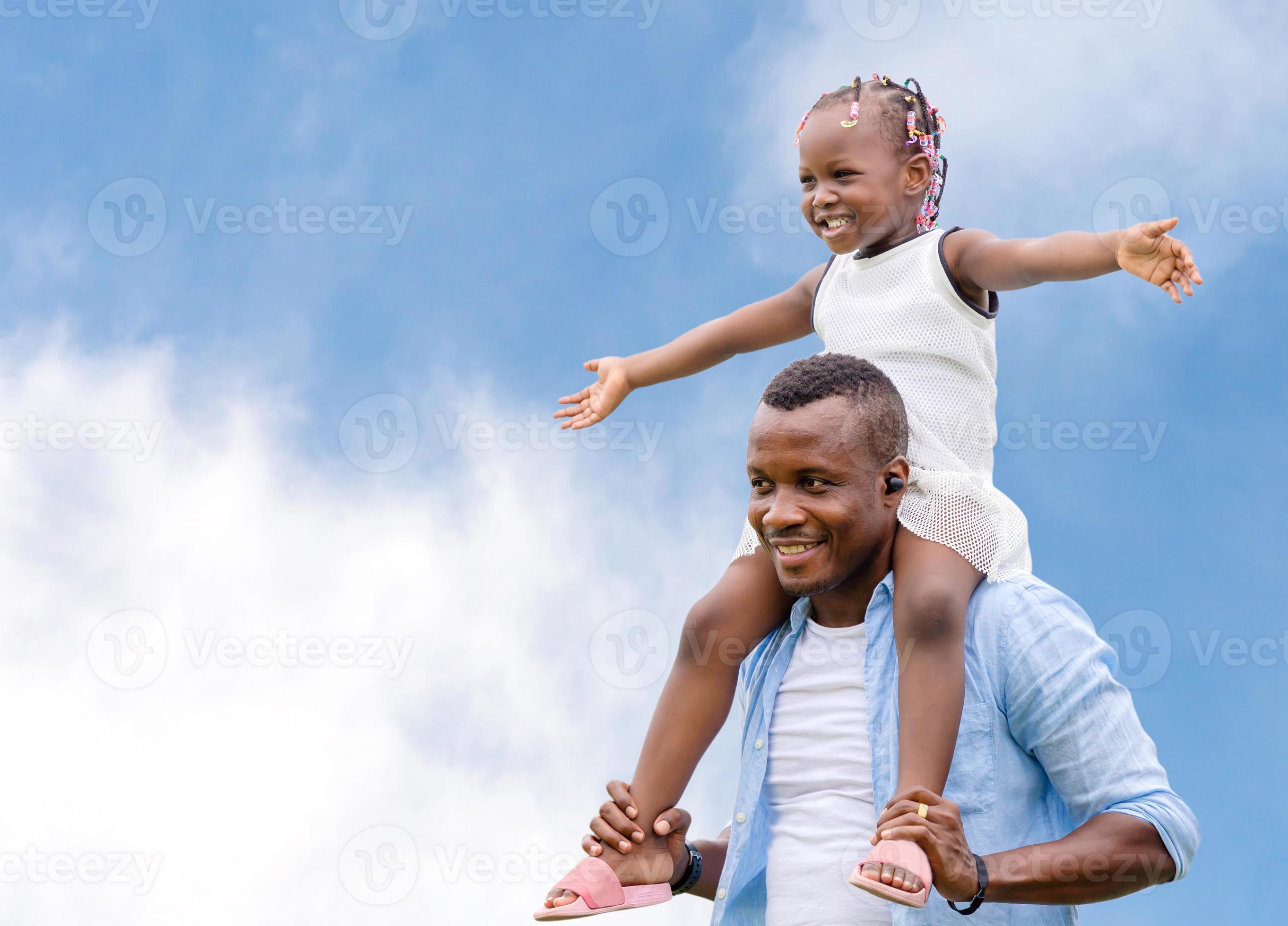 Happy father carrying daughter on shoulders, Cheerful african american girl on the shoulders of ...
