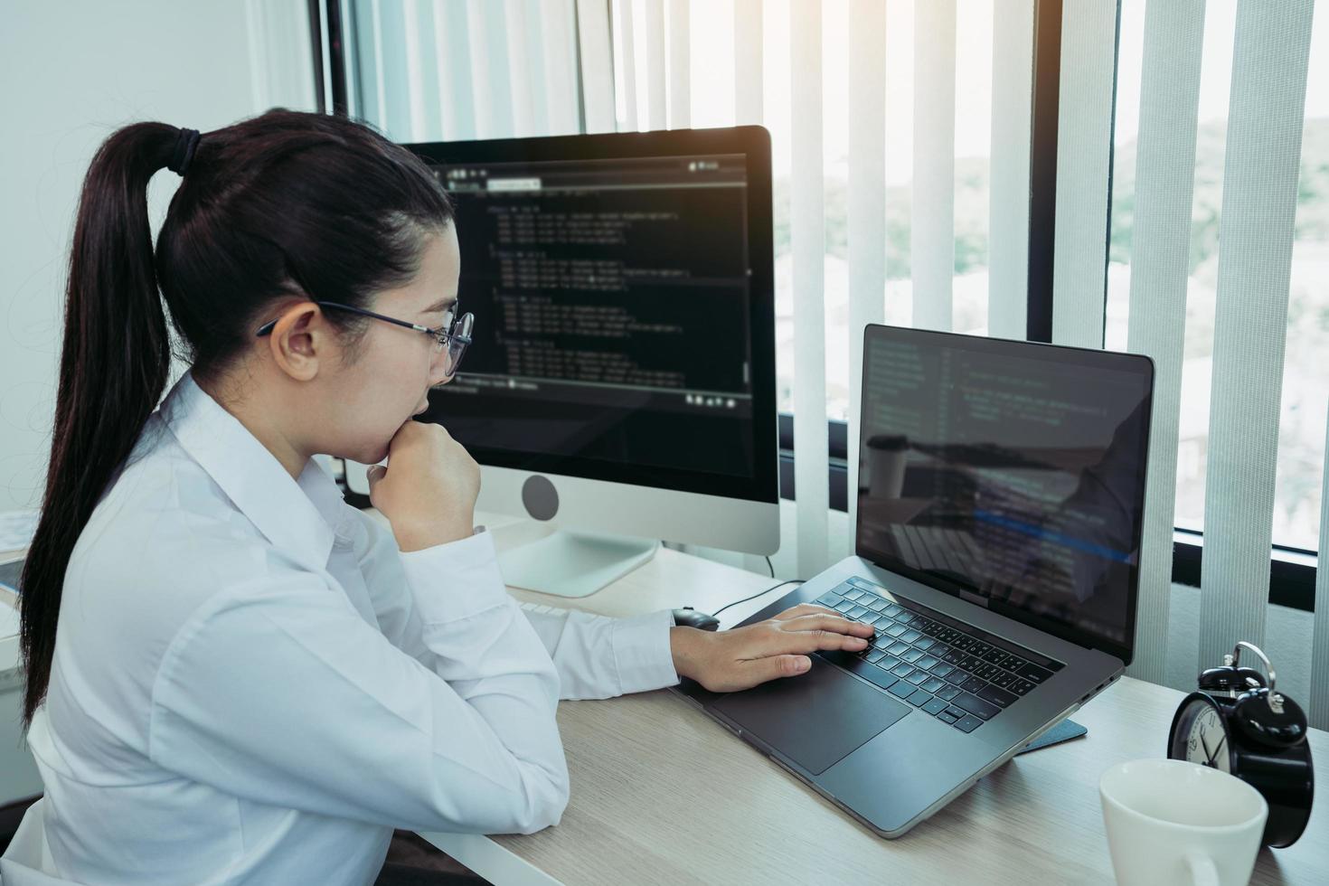 Asian female software developer is worried about analyzing code-based systems at his office ...