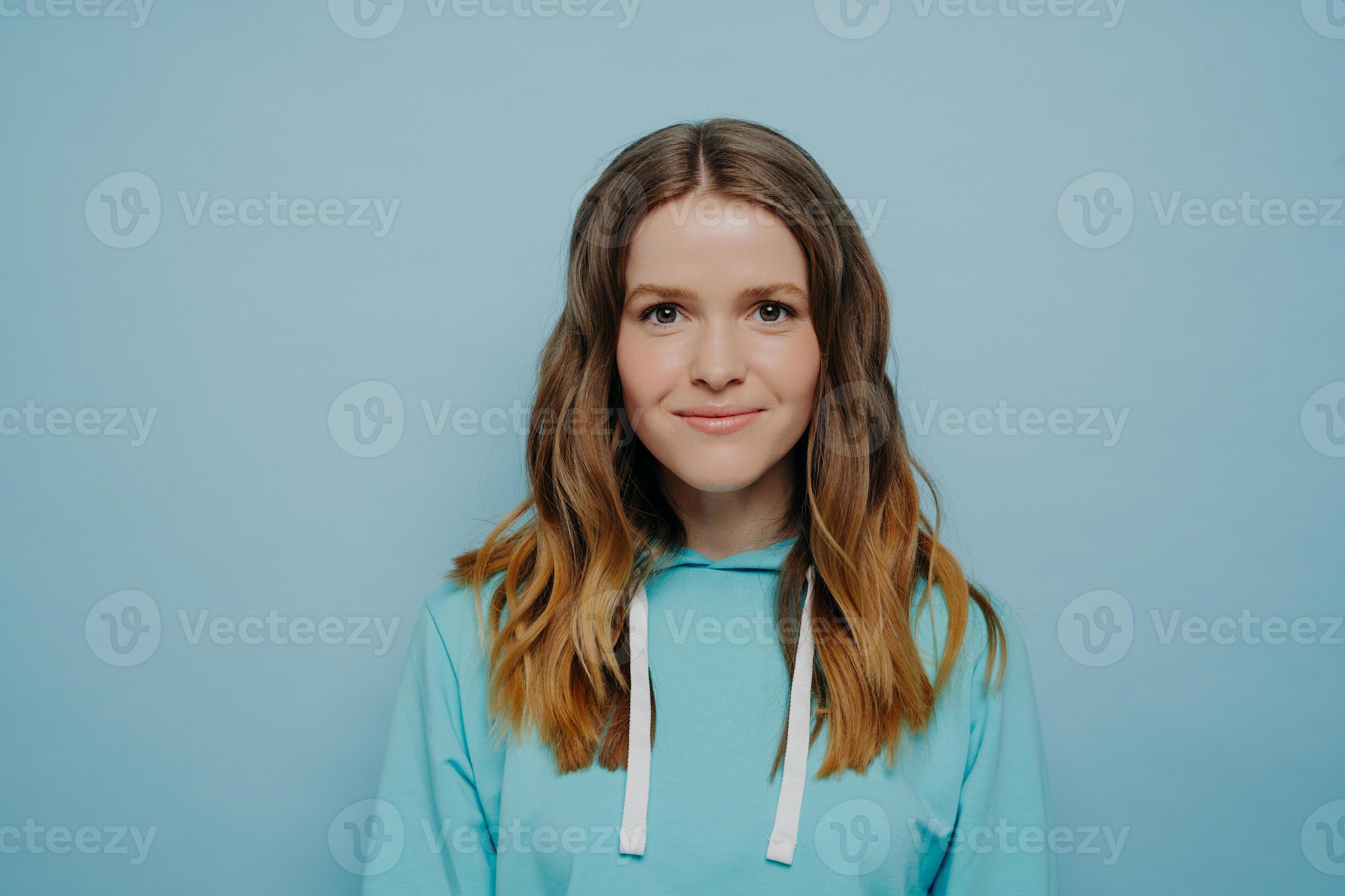 Smiling teenage girl looking at camera posing isolated against blue ...