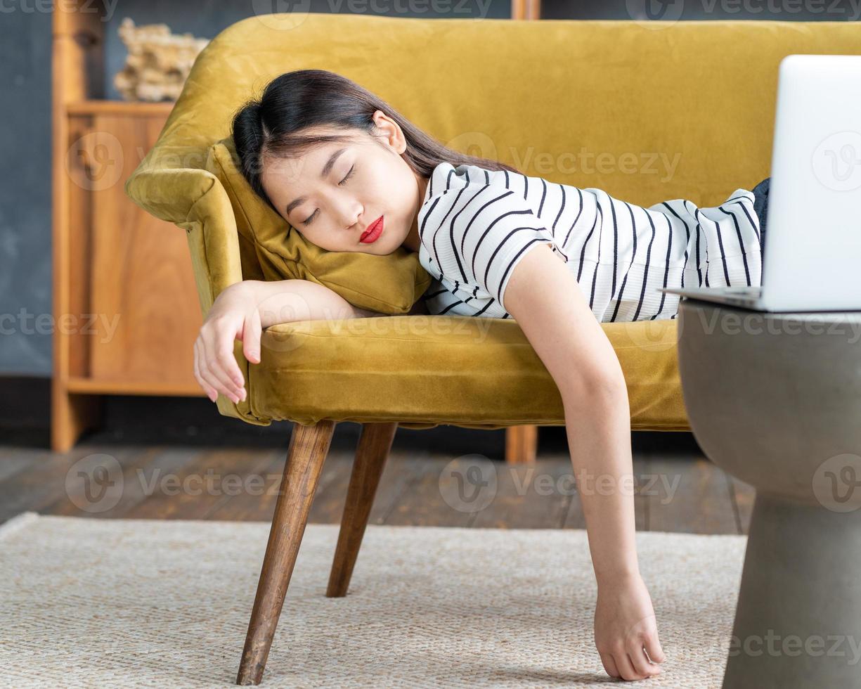 Young Asian girl fell asleep oncouch in front oflaptop. Cute woman is ...