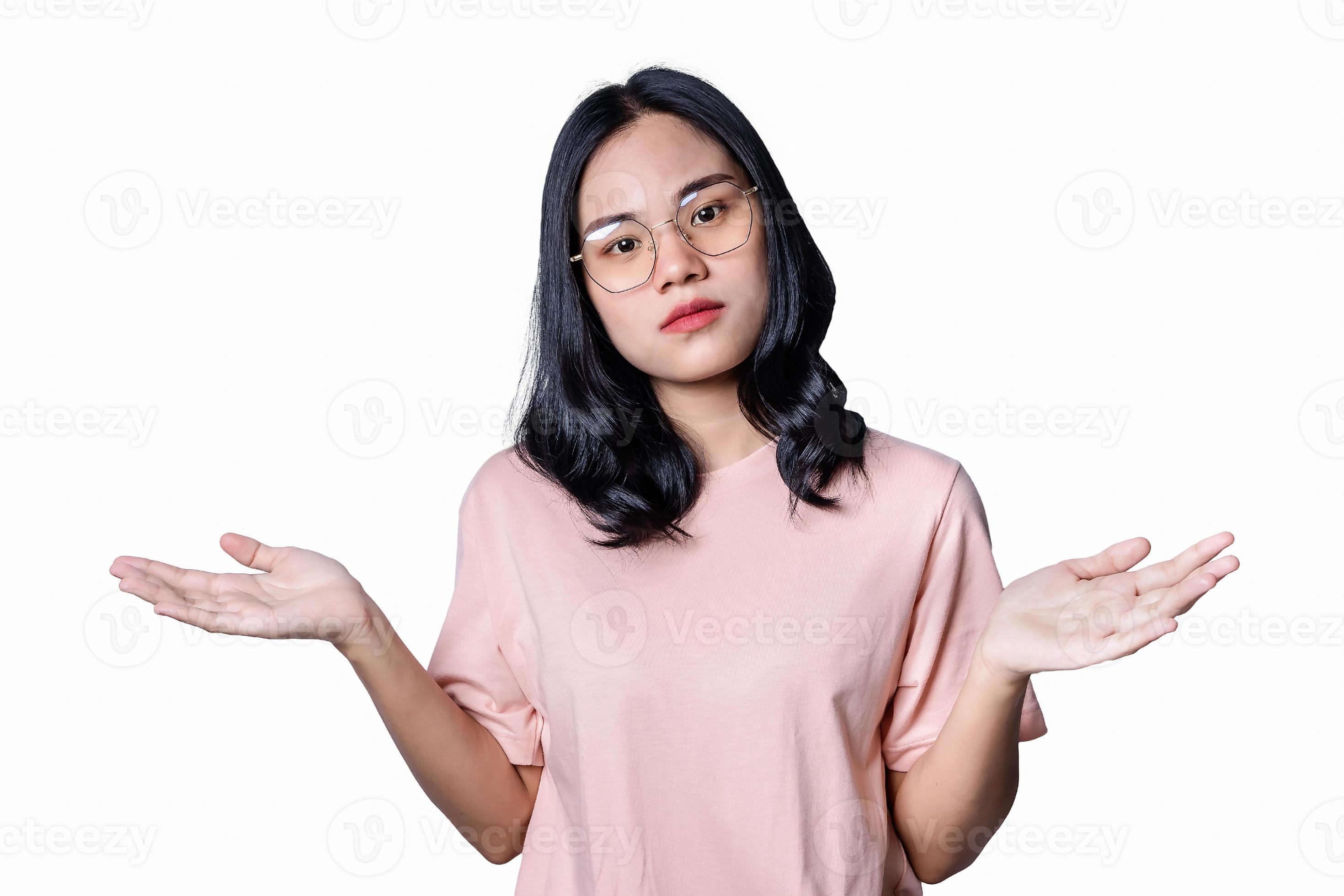 Doubtful young woman wearing glasses shrugging shoulders and spreads ...