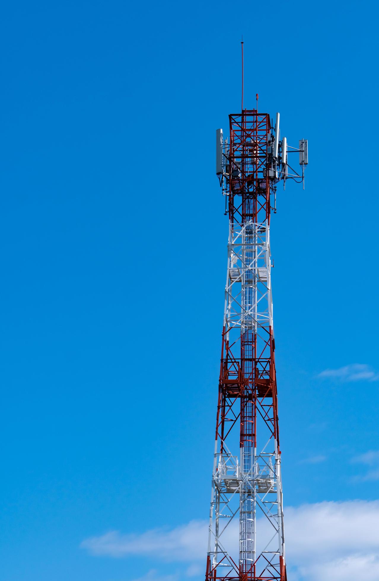 Telecommunication tower with blue sky and white clouds background. Antenna on blue sky. Radio ...