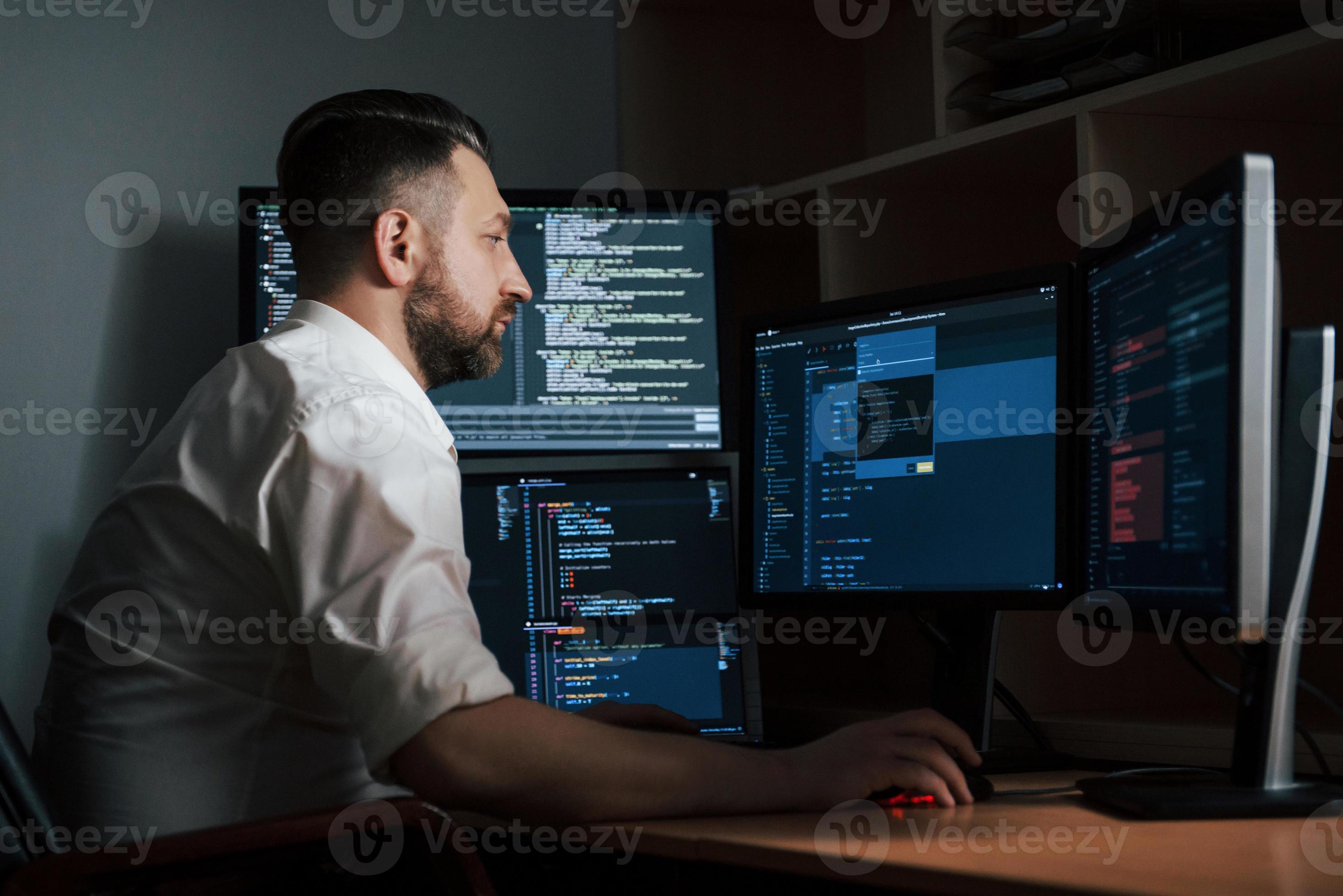 Adult experienced programmer. Bearded man in white shirt works in the ...
