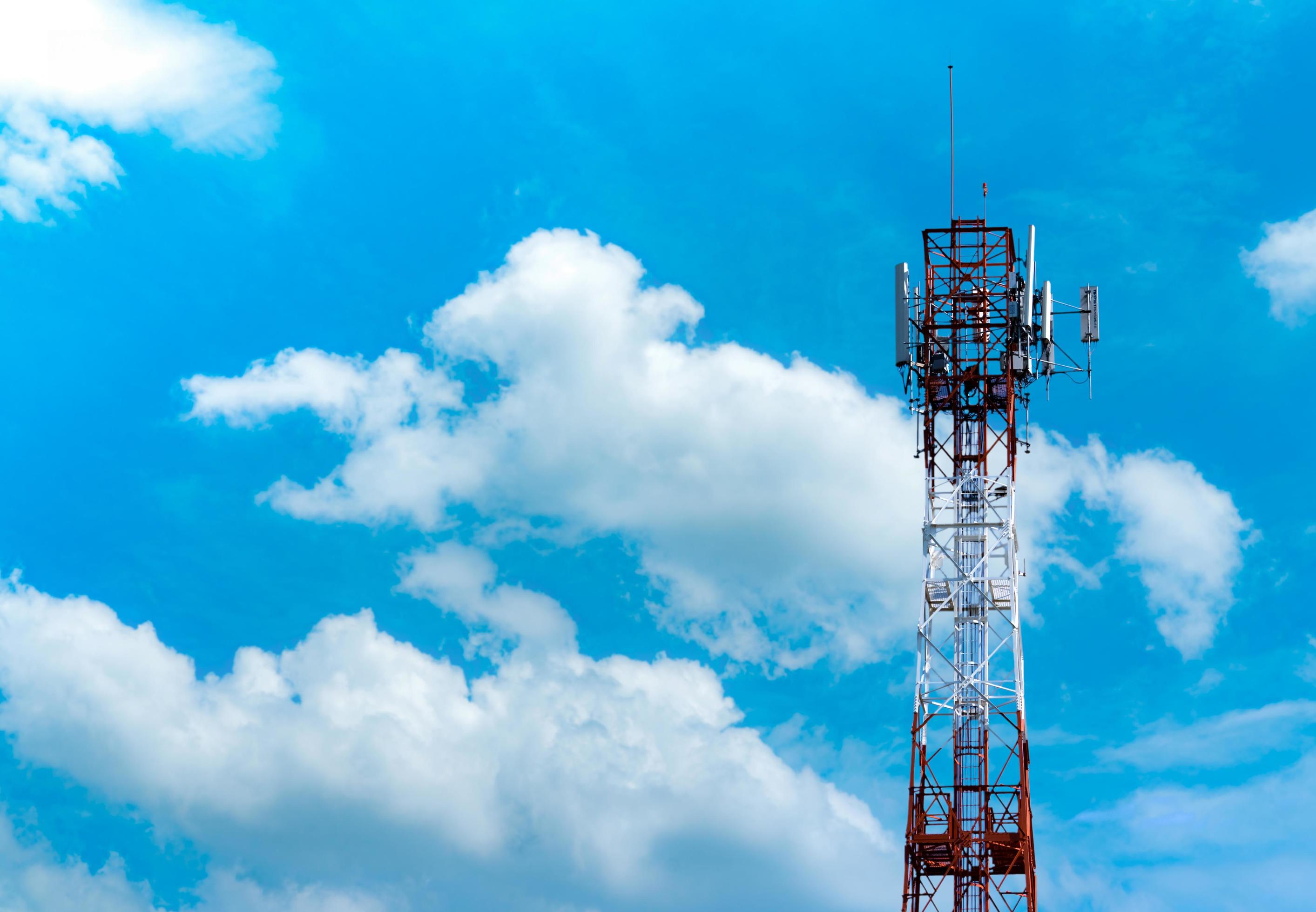 Telecommunication tower with blue sky and white clouds background. Antenna on blue sky. Radio ...