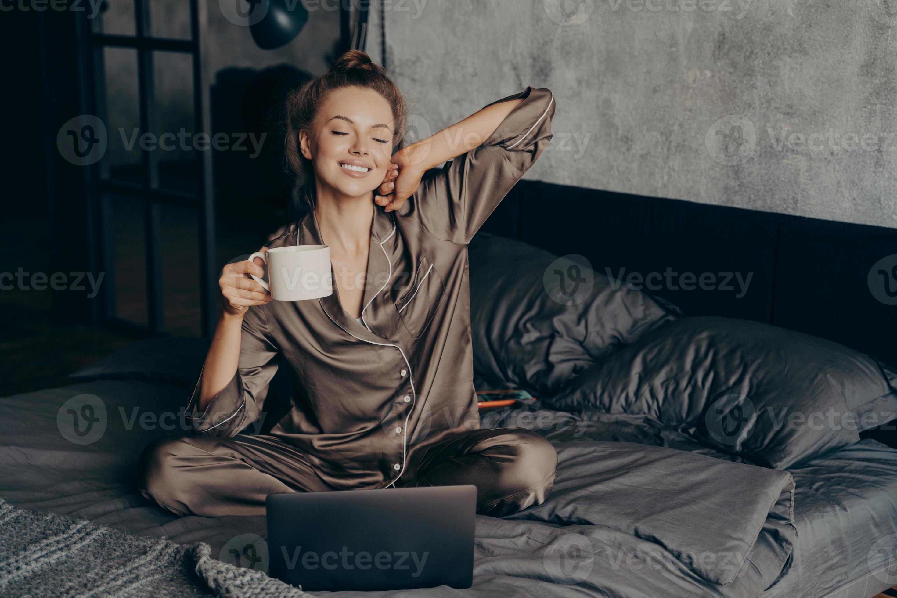 Relaxed Young Brunette Female In Satin Pajama Having Her Cup Of Coffee