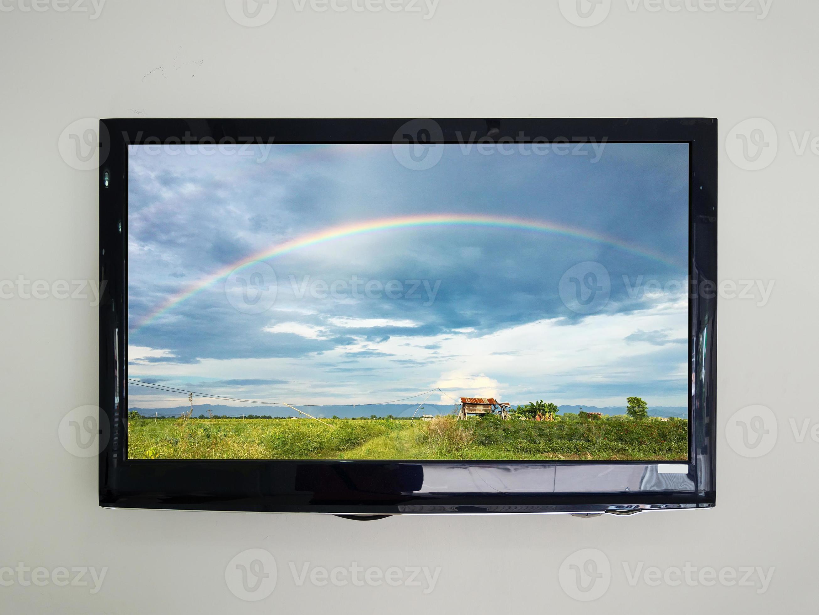 Led tv on the wall background with rainbow in the sky over agriculture ...