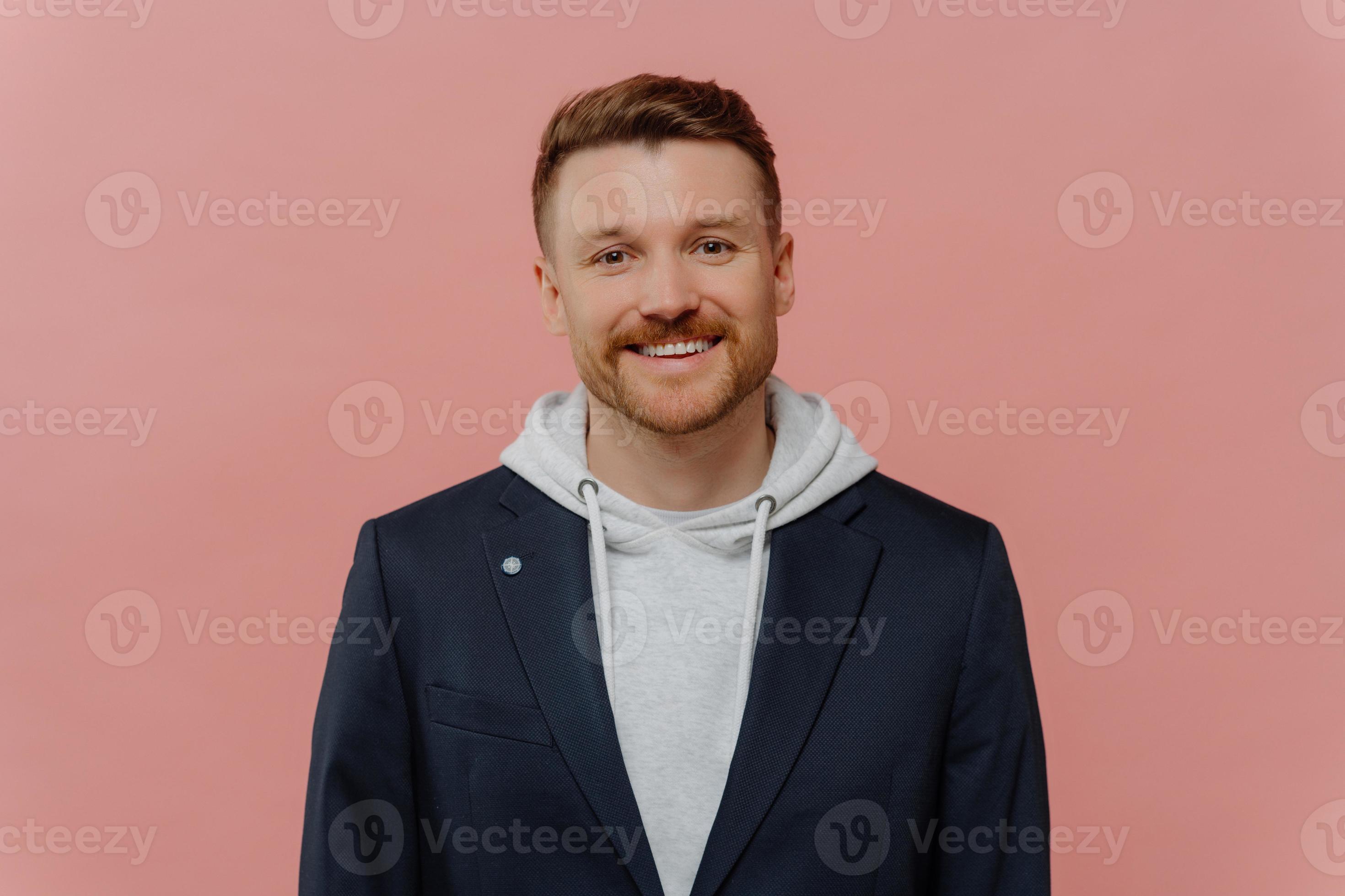 Indoor shot of handsome Caucasian man smiles toothily dressed in hoodie ...