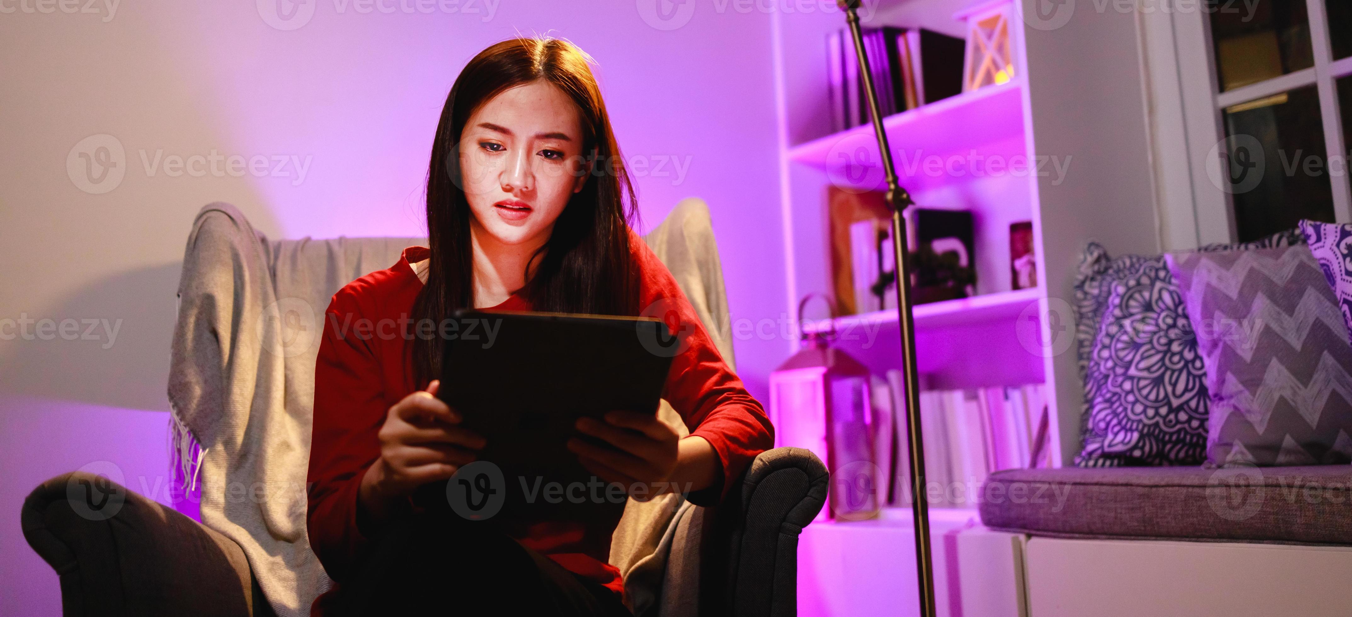 Attractive Asian Girl Sitting On The Sofa And Using A Tablet At Home At The Night Time 8392714 1234