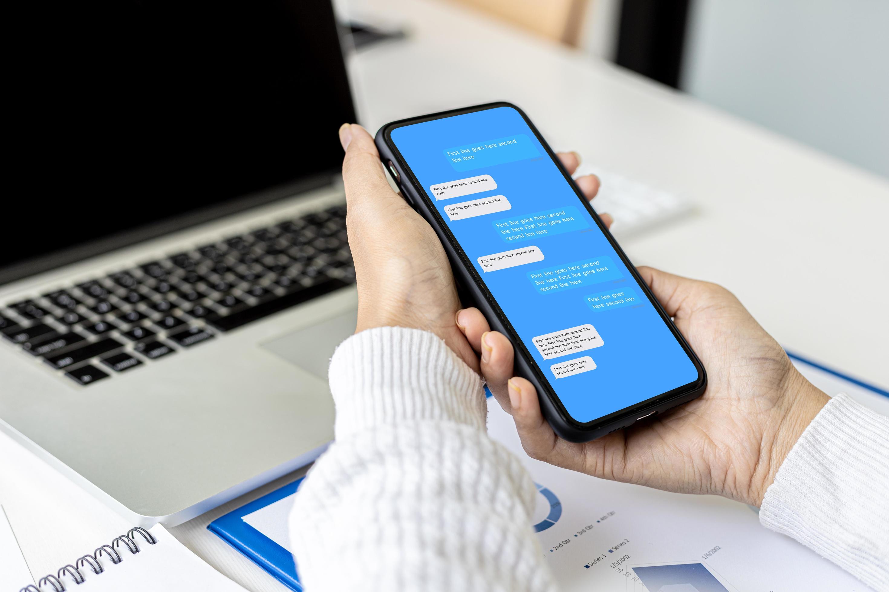 A person holding a smartphone on a screen showing text messages talking ...