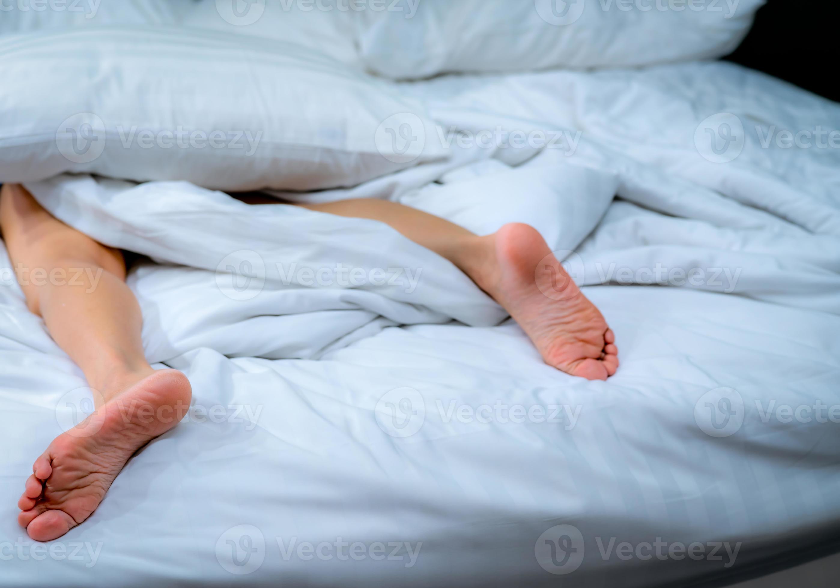 Close Up Woman Bare Feet On The Bed Over White Blanket And Bed Sheet In The Bedroom Of Home Or