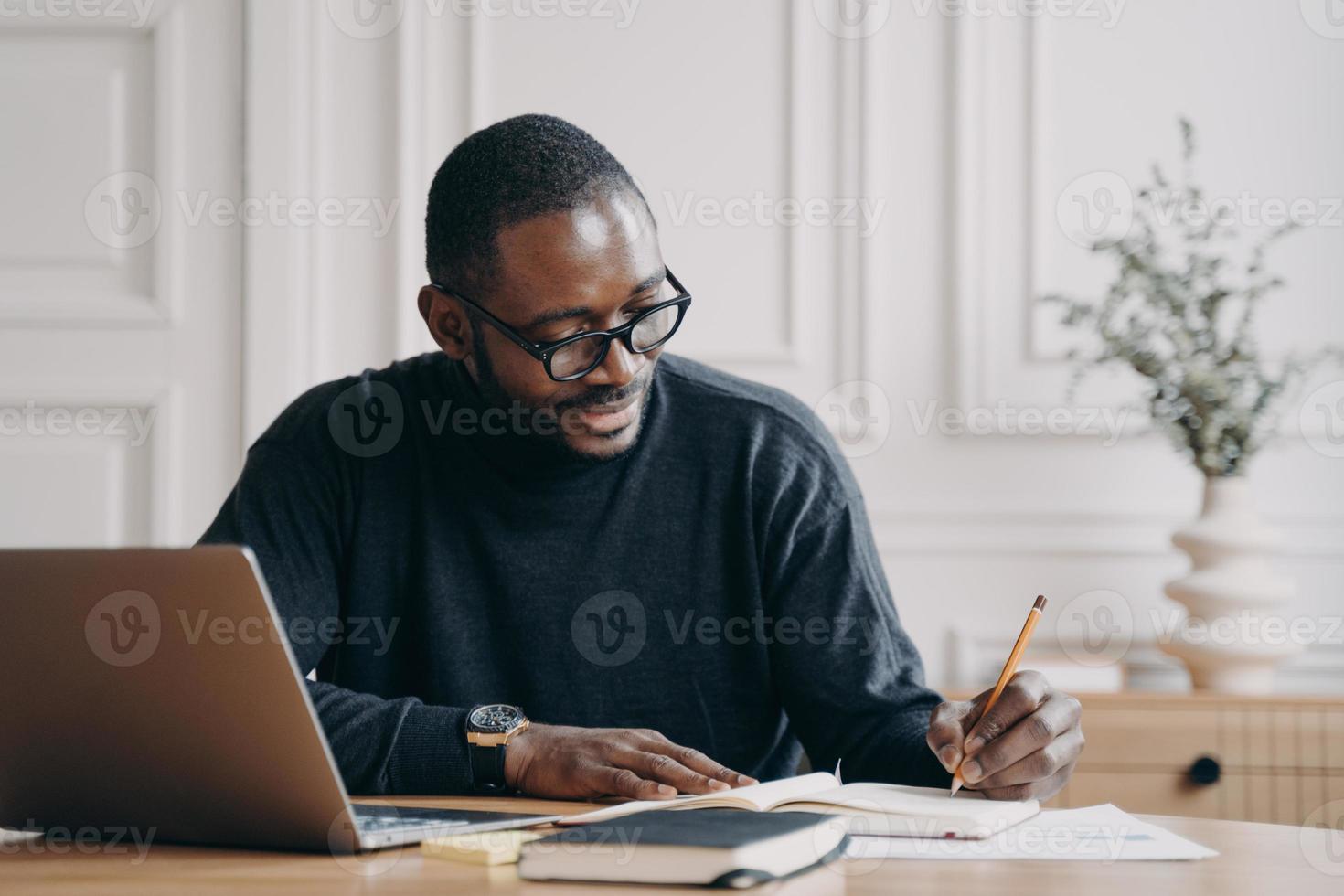 Confident young Afro american businessman working remotely online while ... Confident young Afro american businessman working remotely online while ...