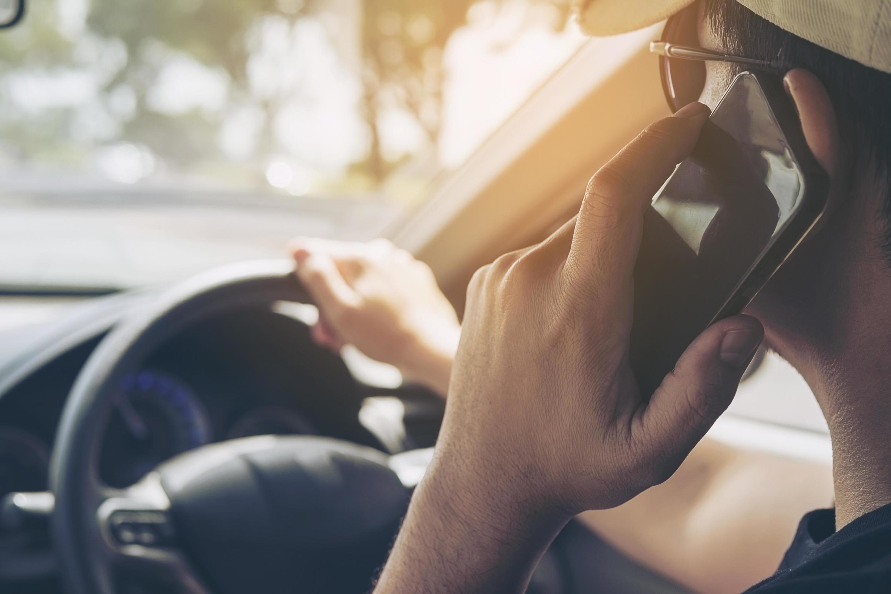 Close up of a man driving car dangerously while using mobile phone ...