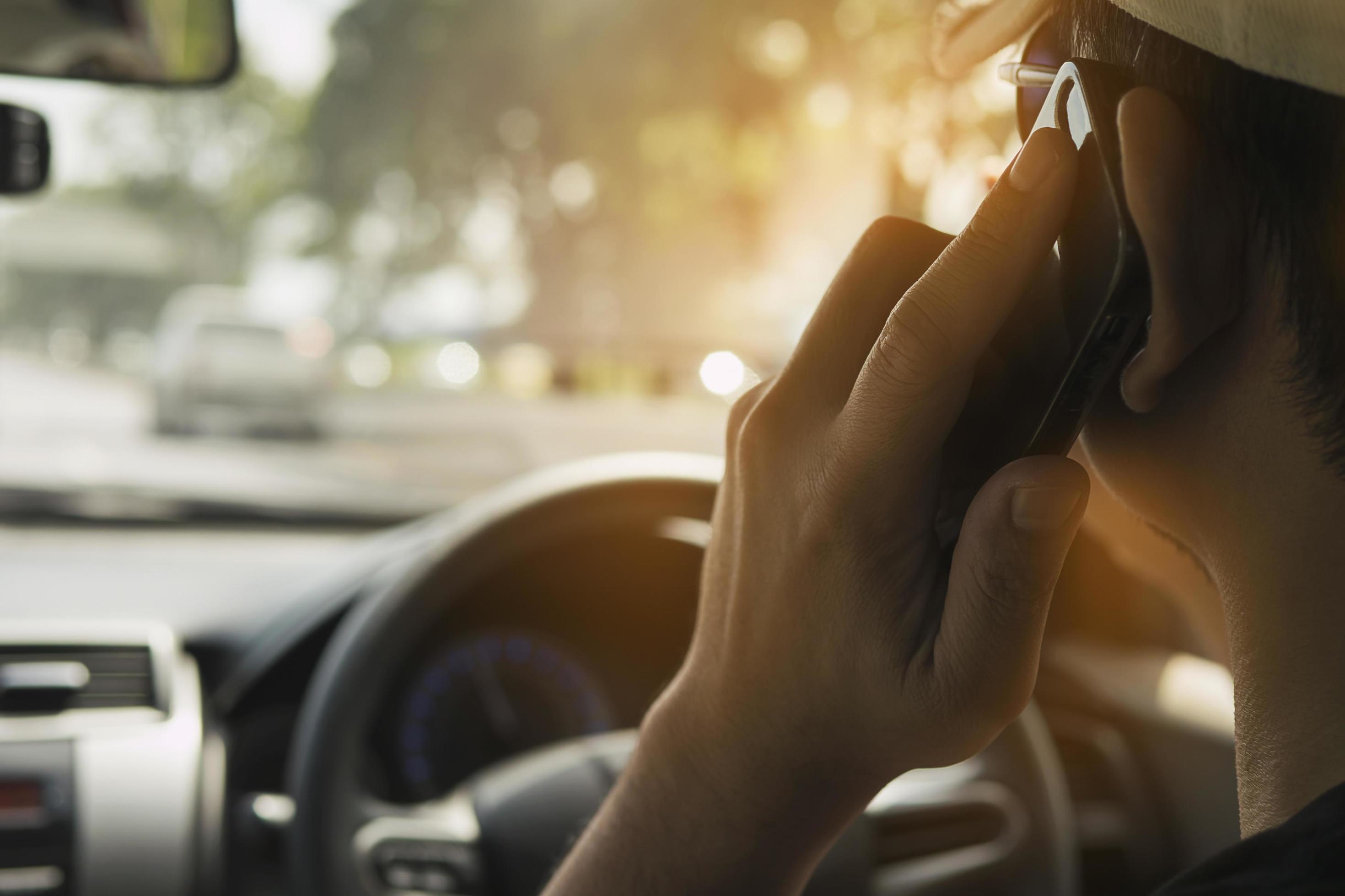 Close up of a man driving car dangerously while using mobile phone ...