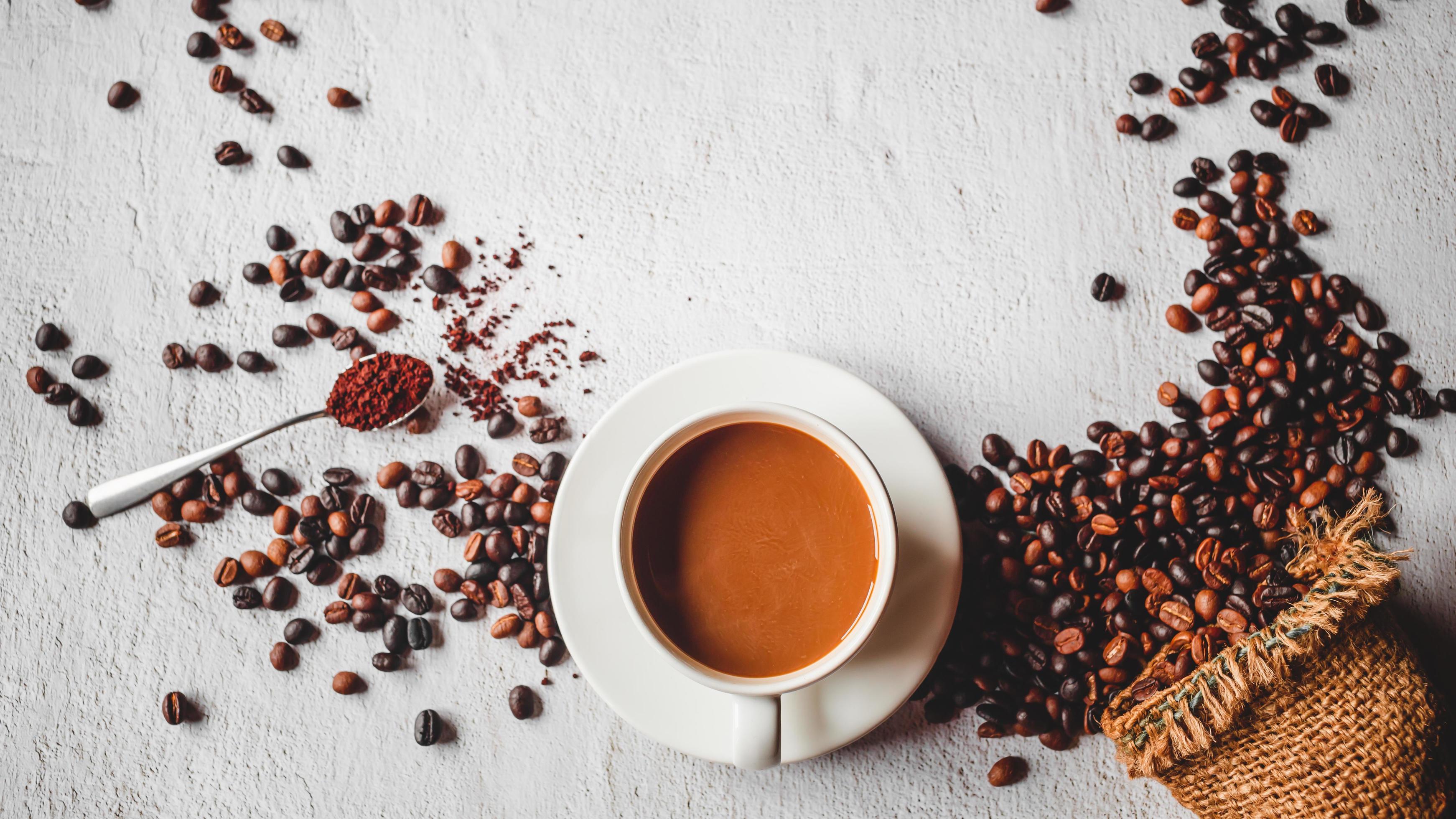 Top view of a coffee cup and coffee powder on a wooden spoon on white background. Coffee beans ...