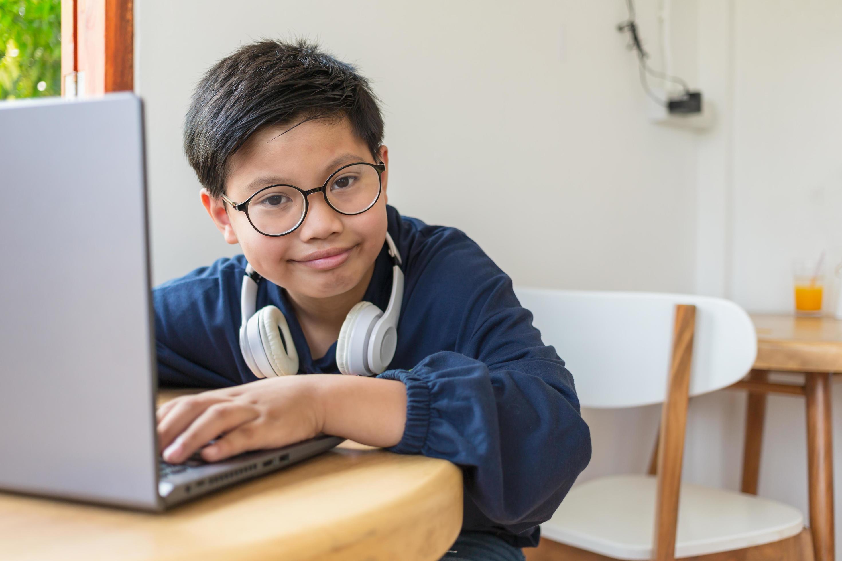 Smart Asian student boy wearing glasses with headphones looking at the ...