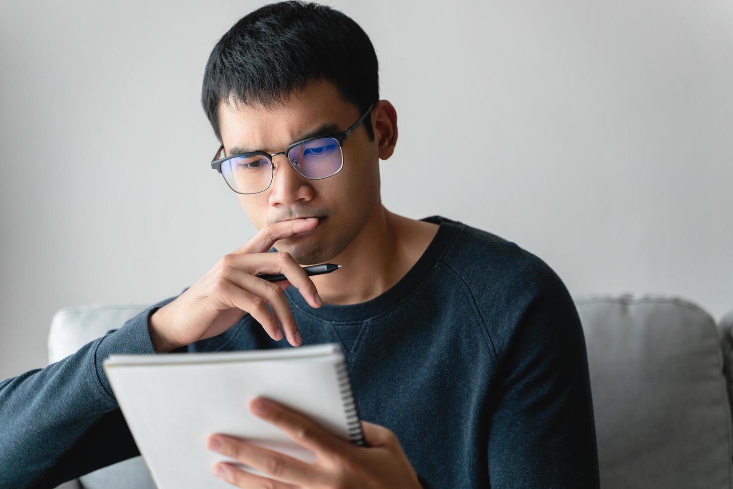 Thoughtful man holding notebook and pen touching chin with thoughtful ... Thoughtful man holding notebook and pen touching chin with thoughtful ...
