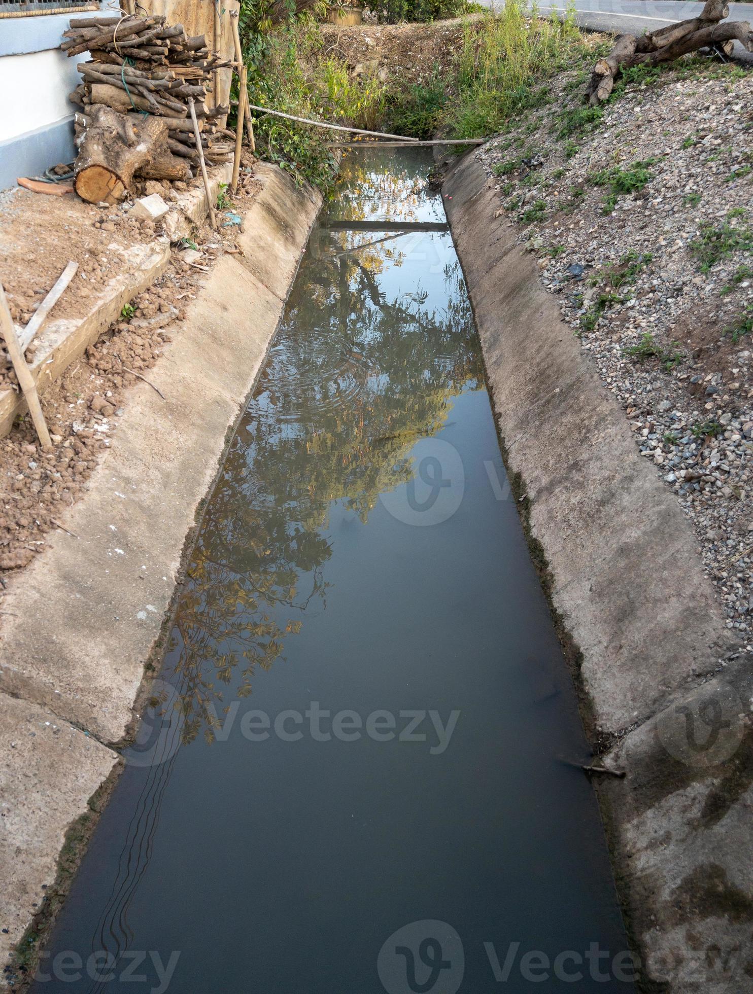 The Concrete Drainage Ditch Runs In Front Of A Farmer s House 9392151 the-concrete-drainage-ditch-runs-in-front-of-a-farmer-s-house-9392151