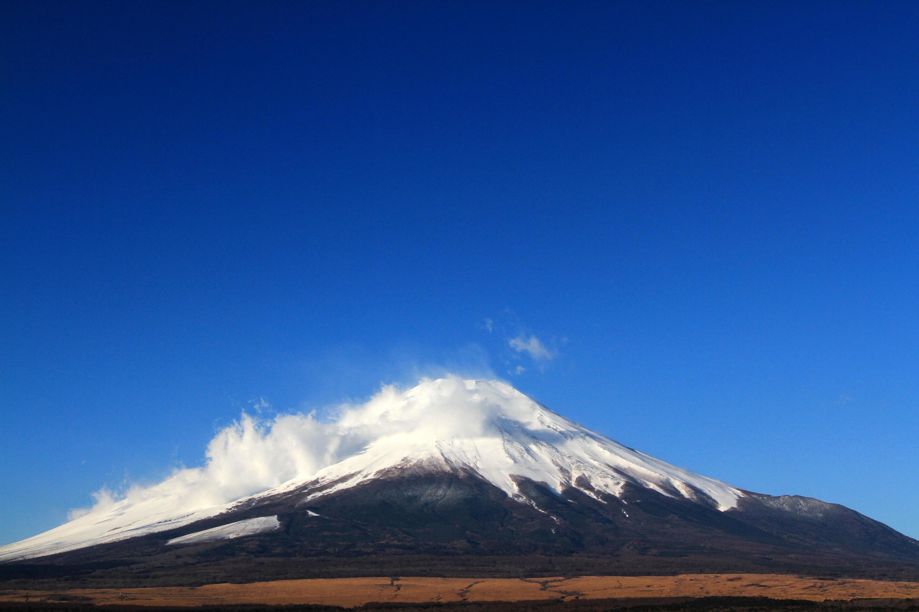 Fuji mountain with snow and fog covered top, lake or sea and clear blue ...
