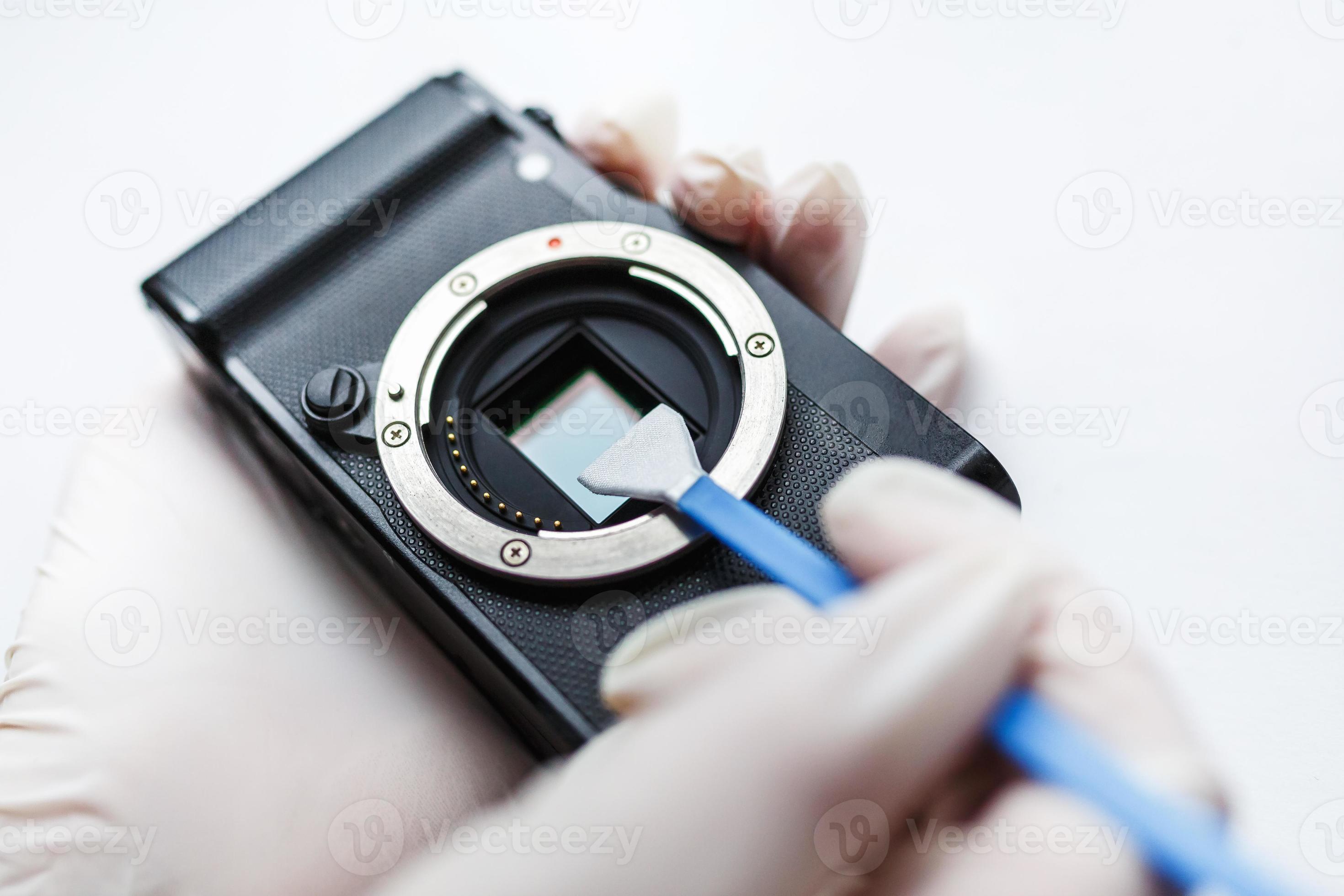 Close-up of mirrorless digital APS-C dirty camera matrix sensor cleaning and maintenance with ...
