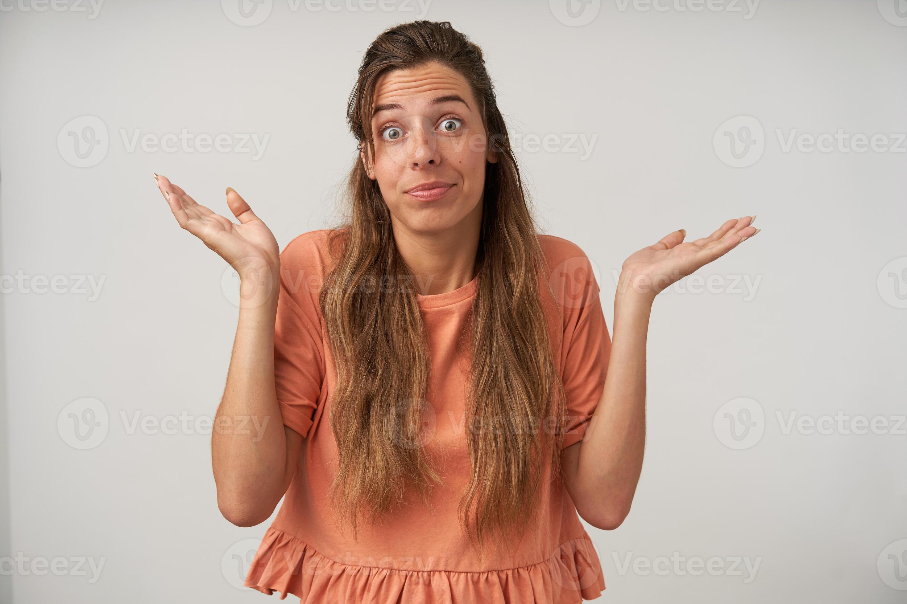 Portrait of young long haired woman shrugging with hands spread ...