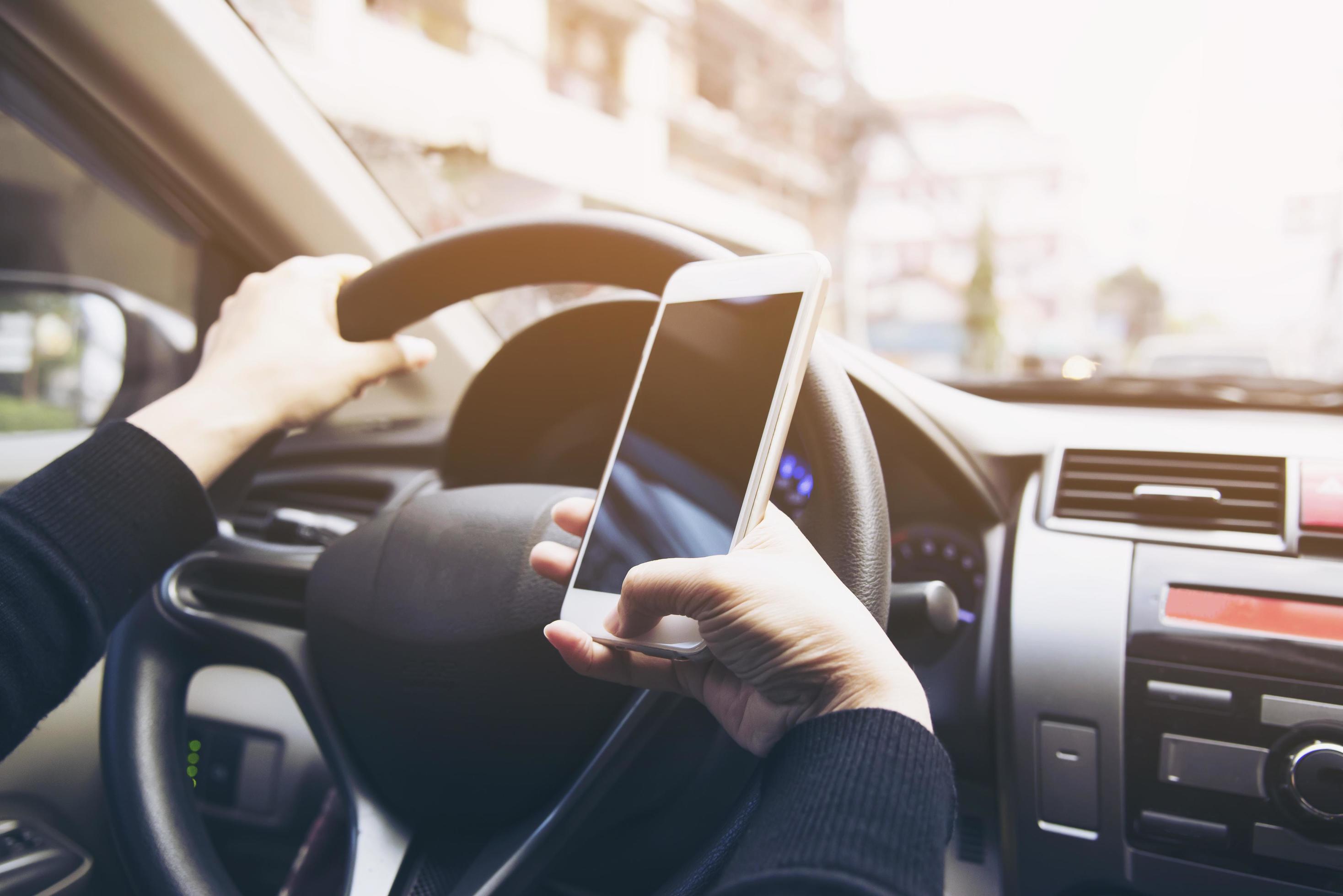 Close up of a woman driving car dangerously while using mobile phone ...