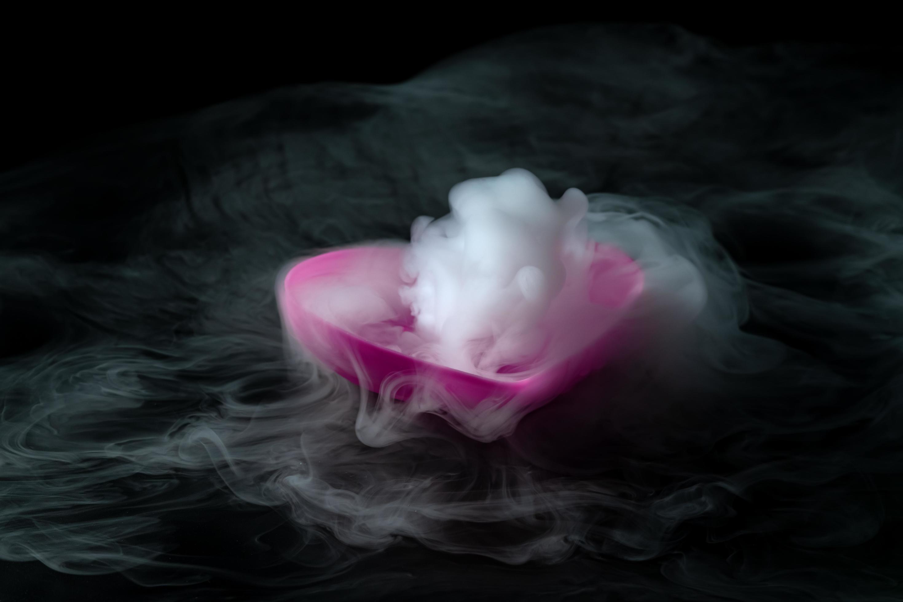 smoke of dry ice with pink heart shaped cup isolated on black ...