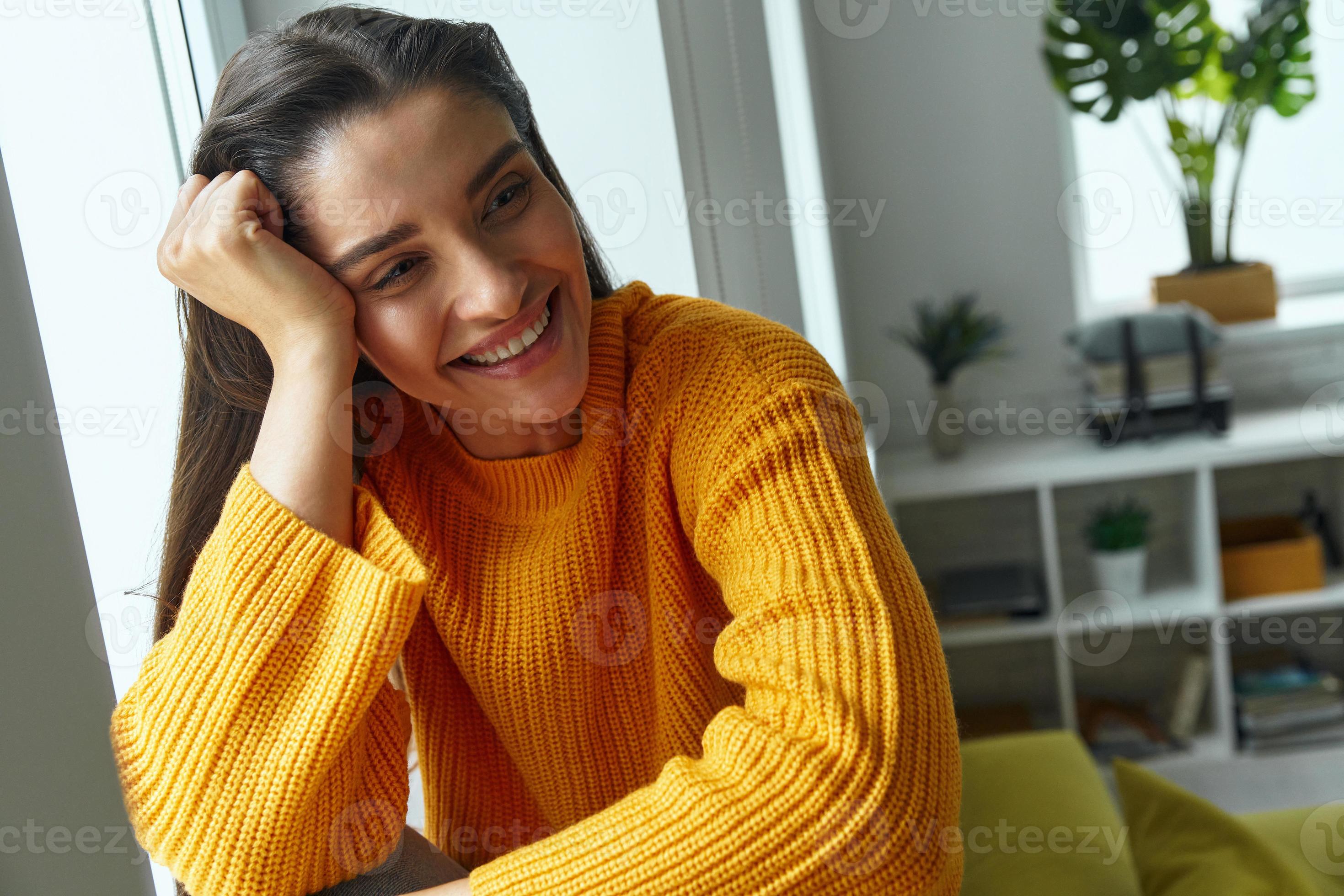 Beautiful young woman leaning head on hand and smiling while sitting on ...