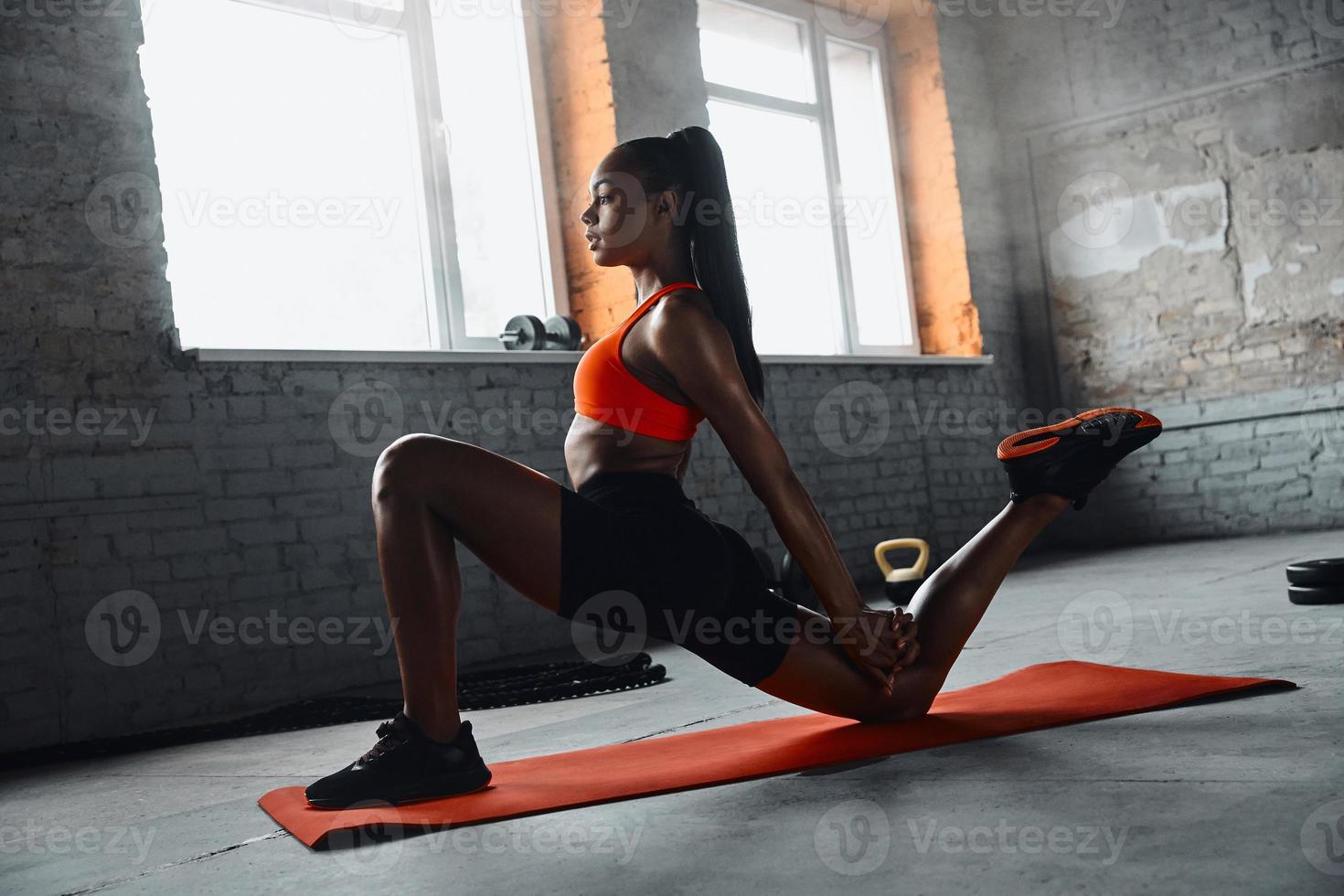 Confident young African woman doing stretching exercises in gym ... Confident young African woman doing stretching exercises in gym ...