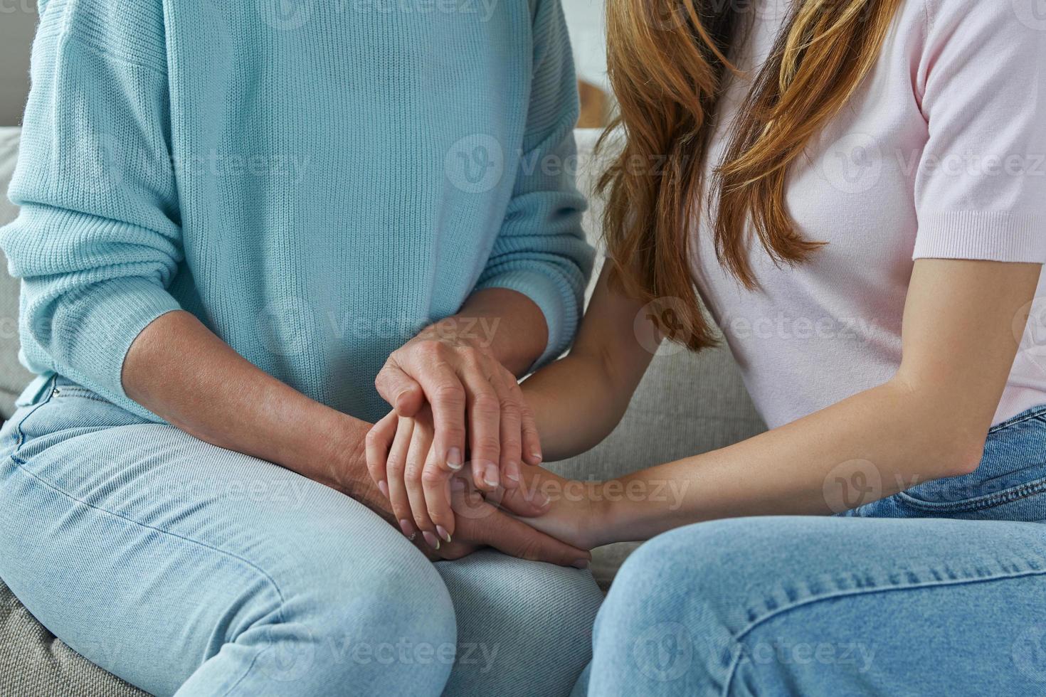 Close Up Of Two Woman Holding Hands While Sitting On The Couch Together