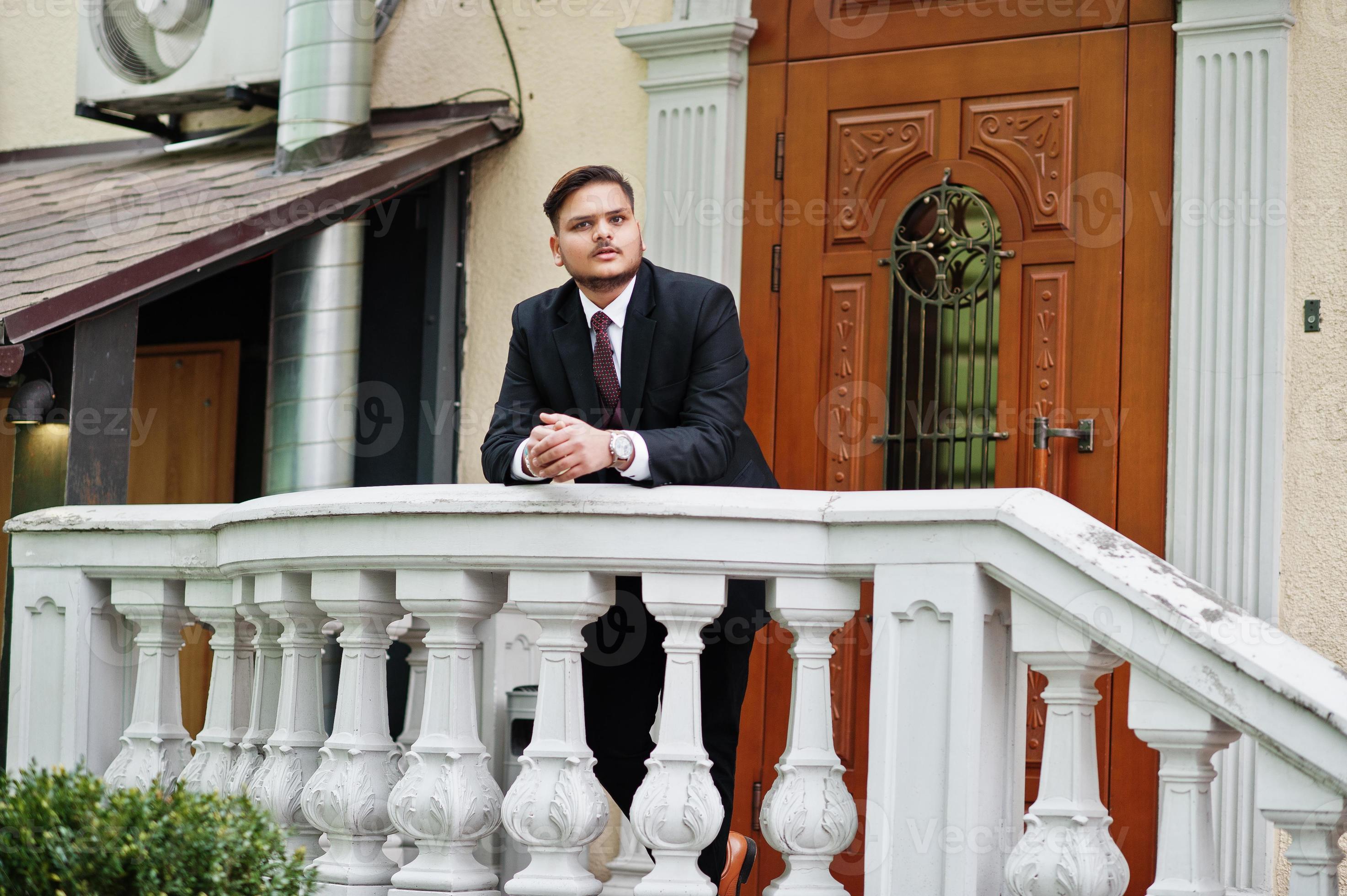 Stylish indian businessman in formal wear leaning on a railing against ...
