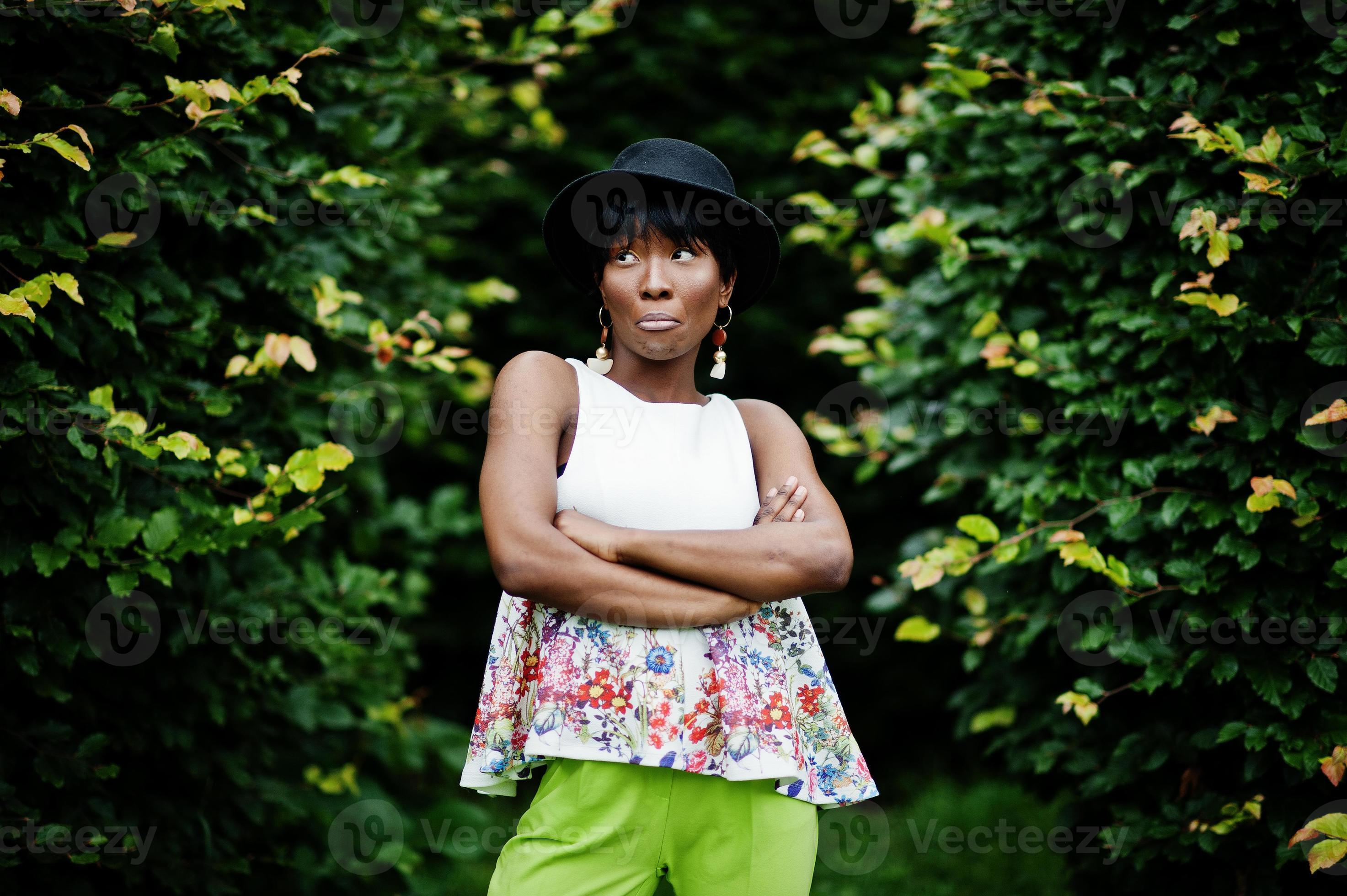 Amazing african american model woman in green pants and black hat posed with different emotions ...
