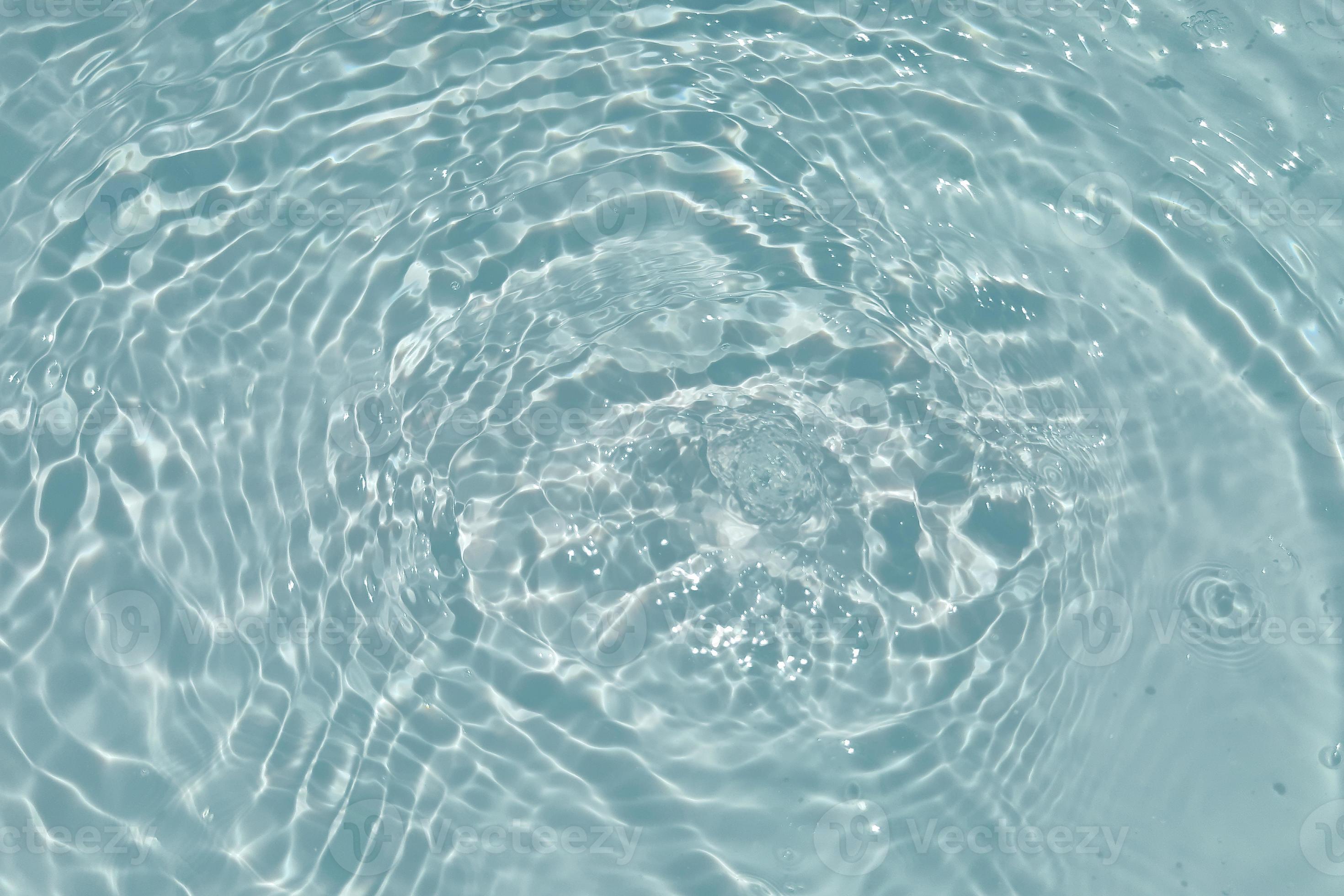 Defocus blurred transparent blue colored clear calm water surface texture with splashes and ...
