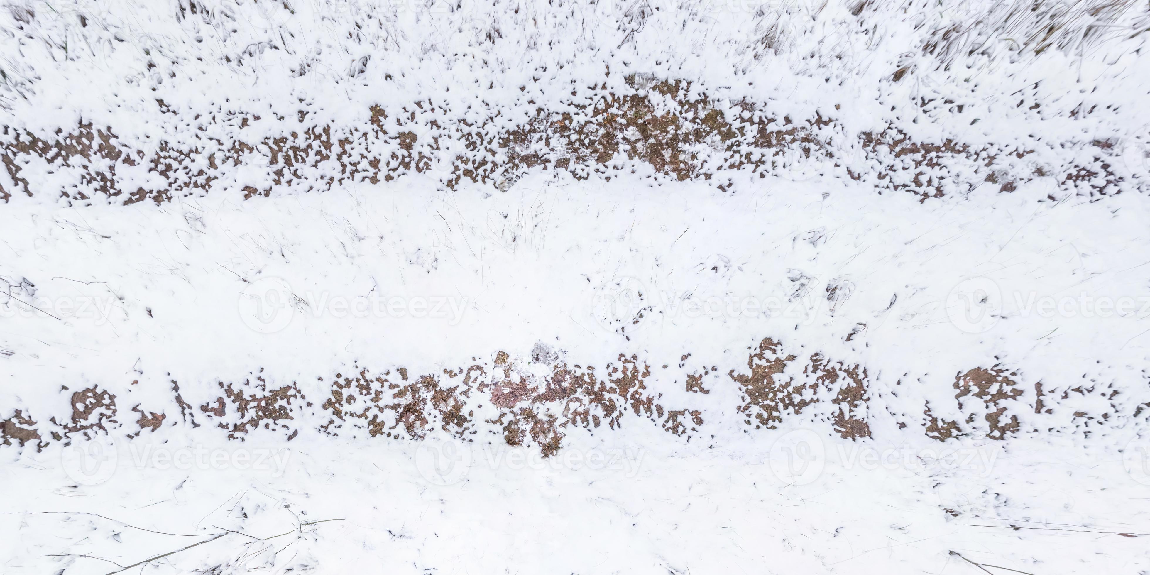 vista panorámica desde arriba sobre la textura del camino de tierra de grava cubierto de nieve ...