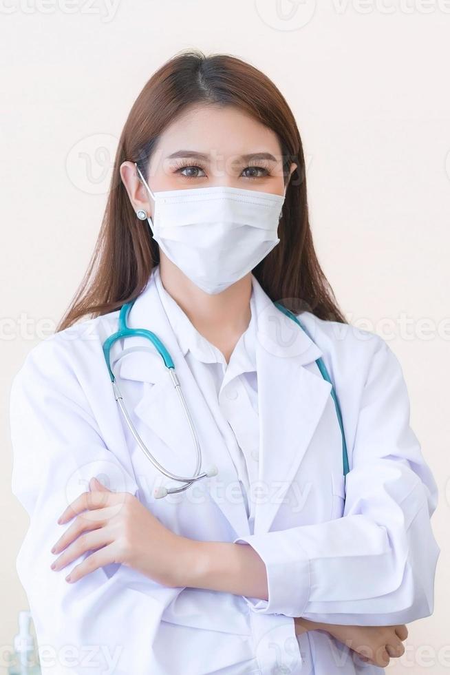 Asian Female Doctor Stood Wearing A White Robe Wearing A Mask And